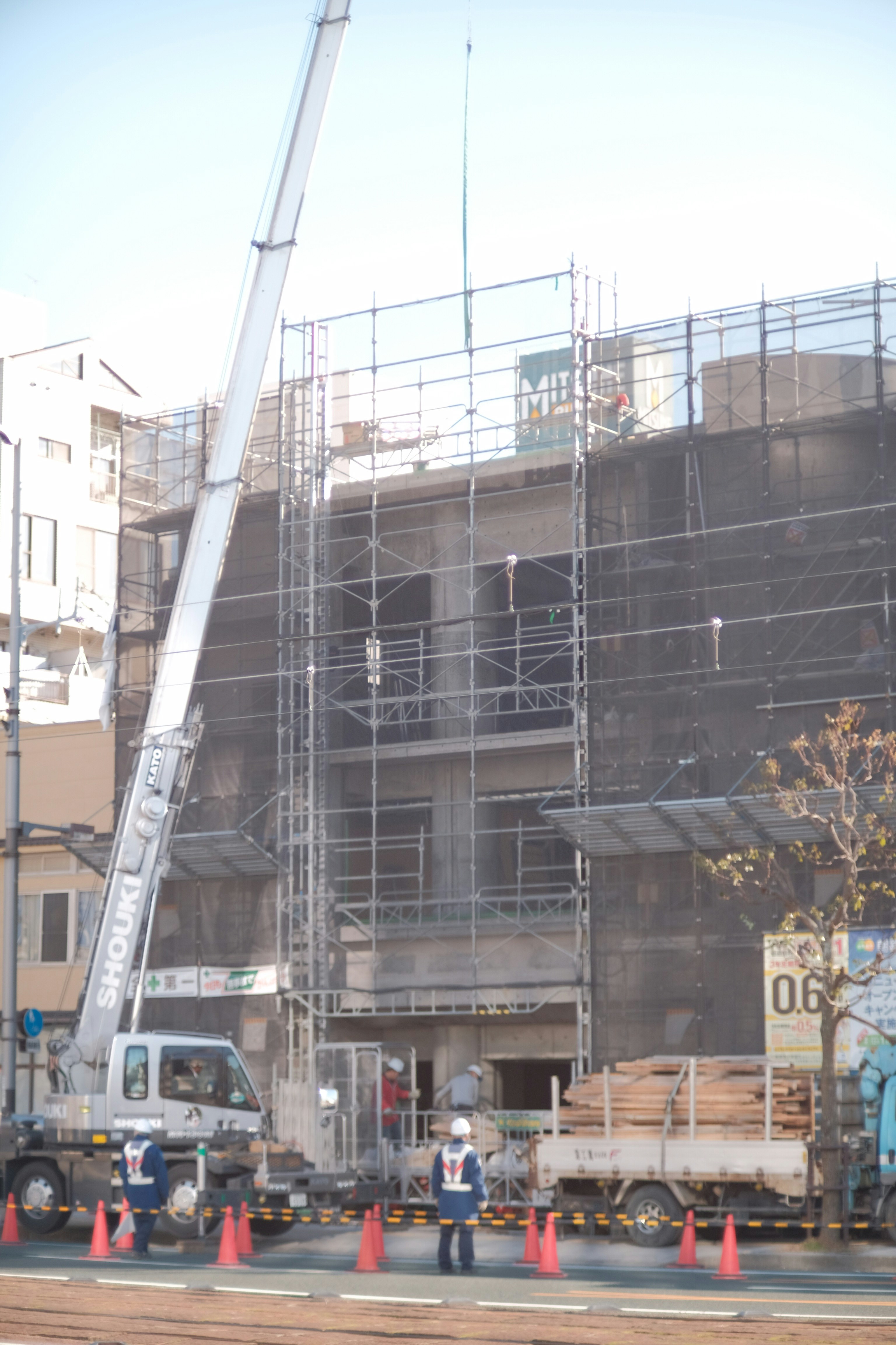 Construction workers engaged in building renovation, with scaffolding and machinery prominently displayed. The scene captures the essence of urban development.