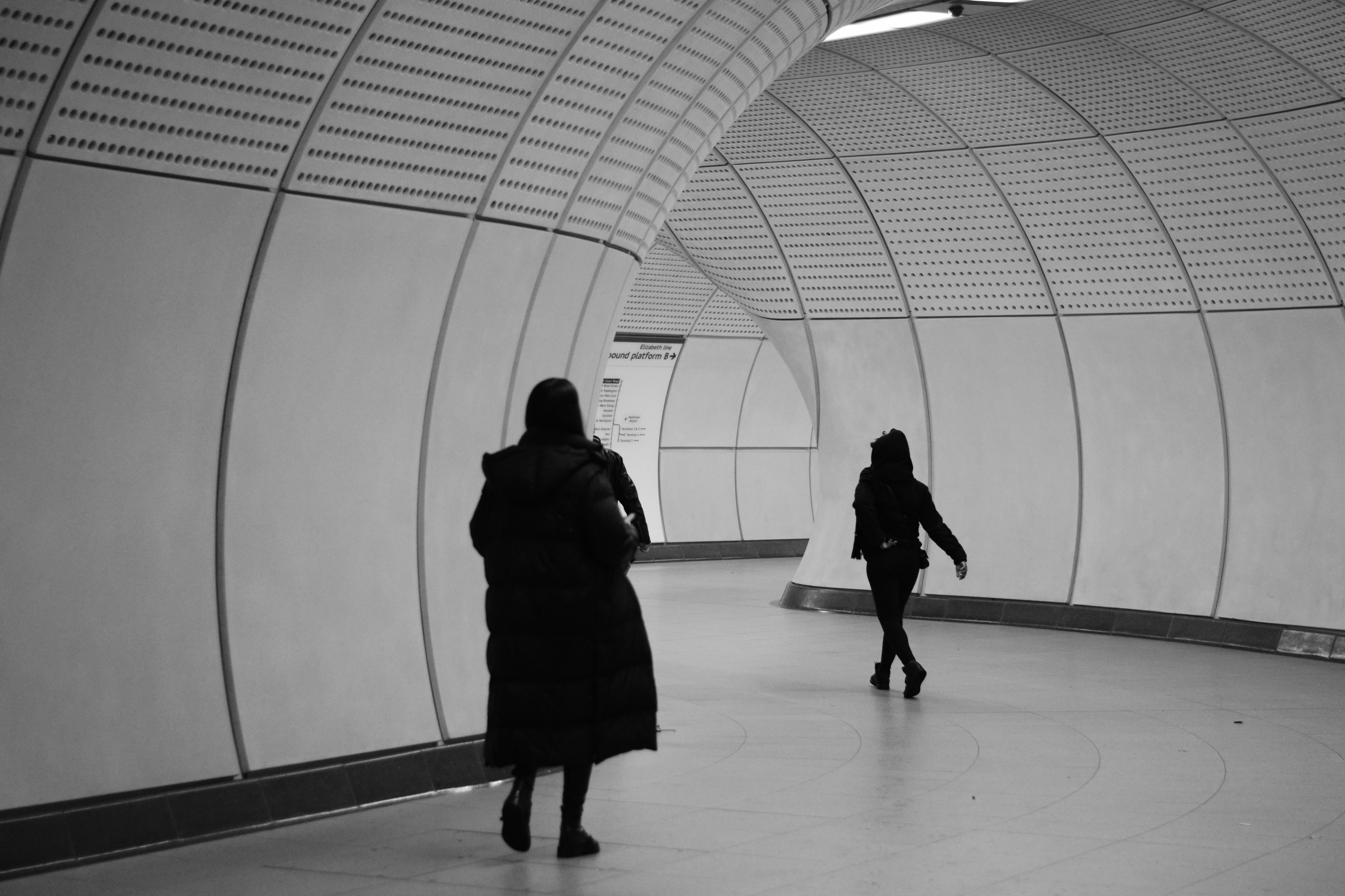 A couple of people walking in a large room with white walls photo ...