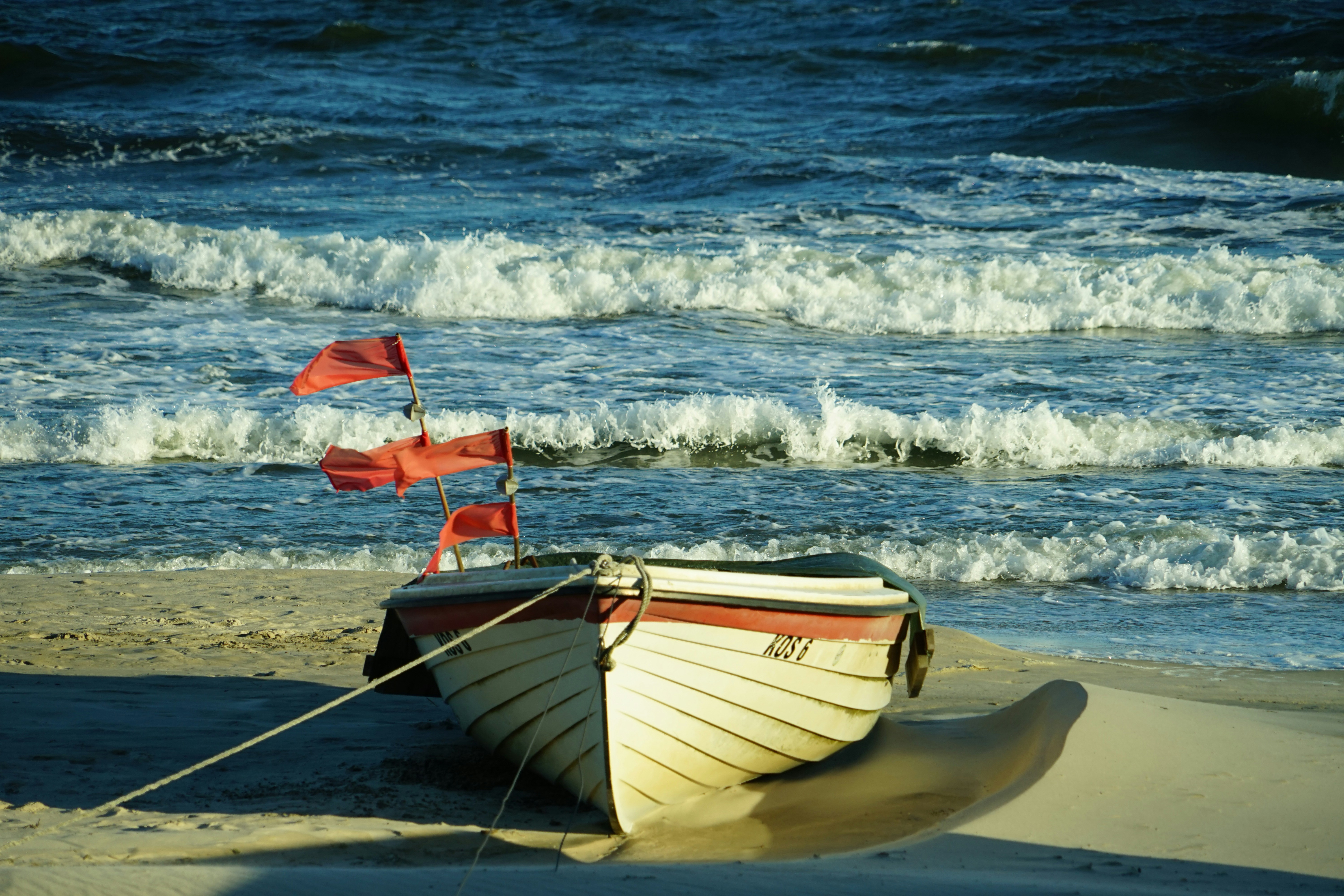 Sunlit Boat with Red Flags Anchored on a Quiet Seaside