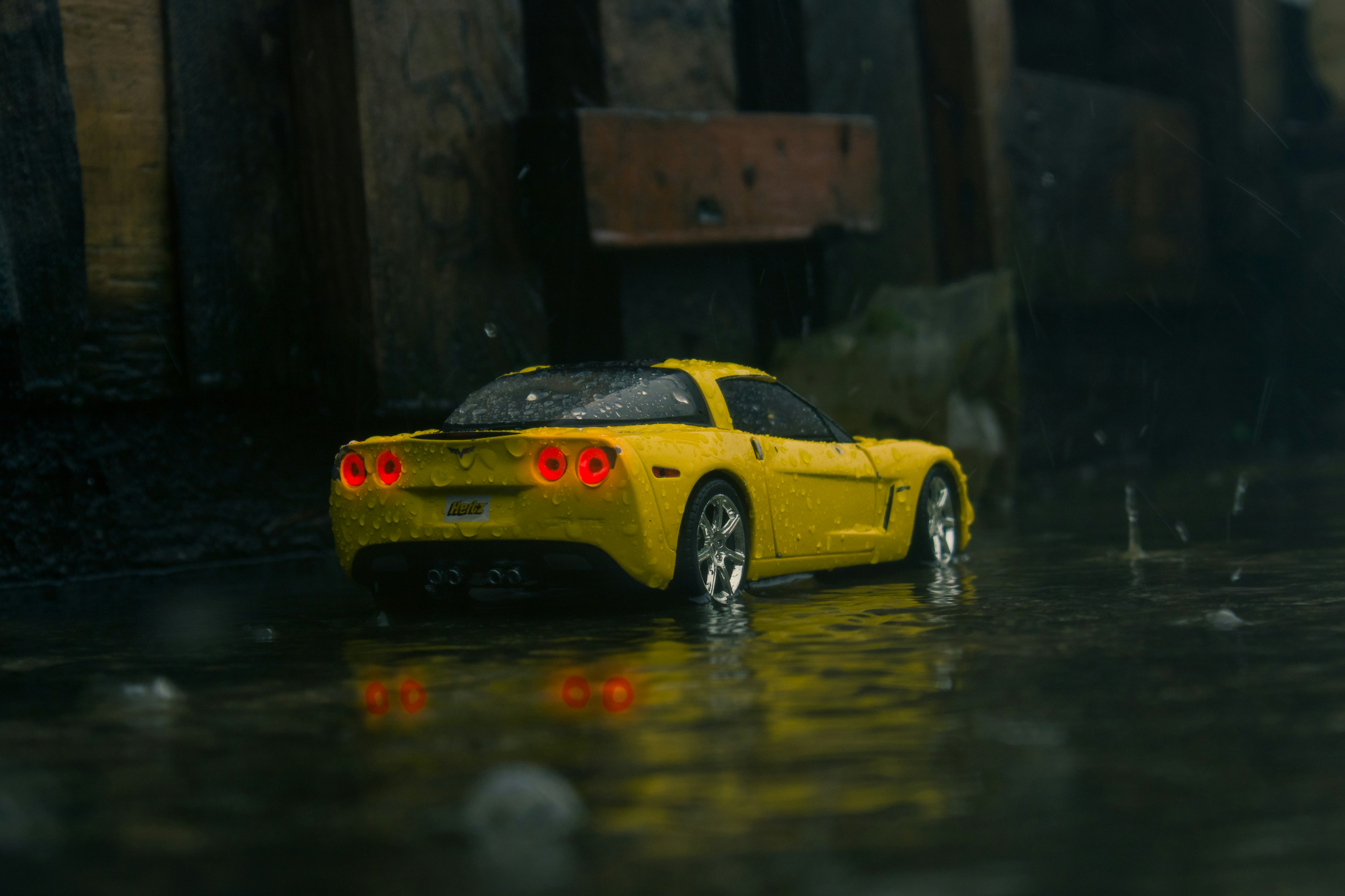 Puddle-Edge Racer: A Yellow Scale-Model Car Beneath a Weathered Pier