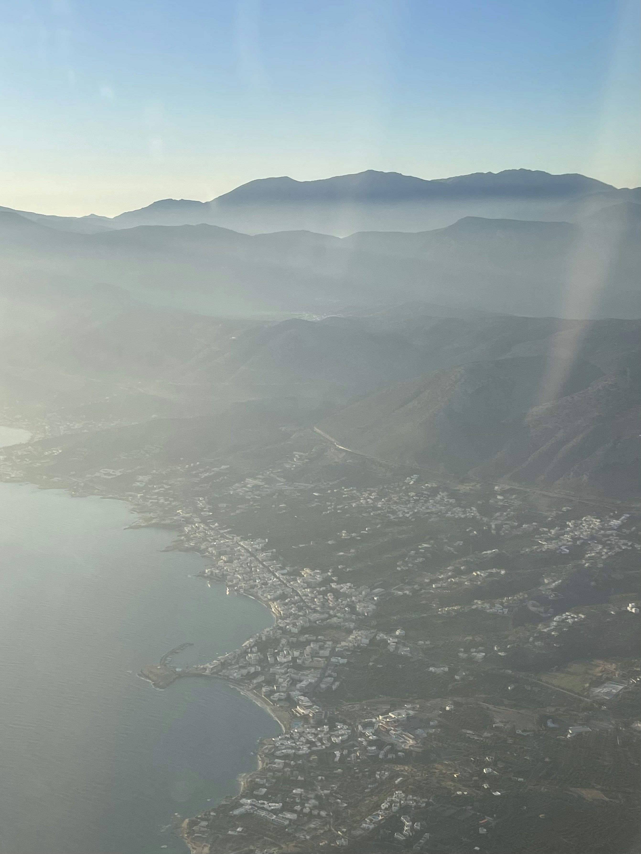 Horizon in the Mist: Coastal Town Framed by Distant Mountain Ridges