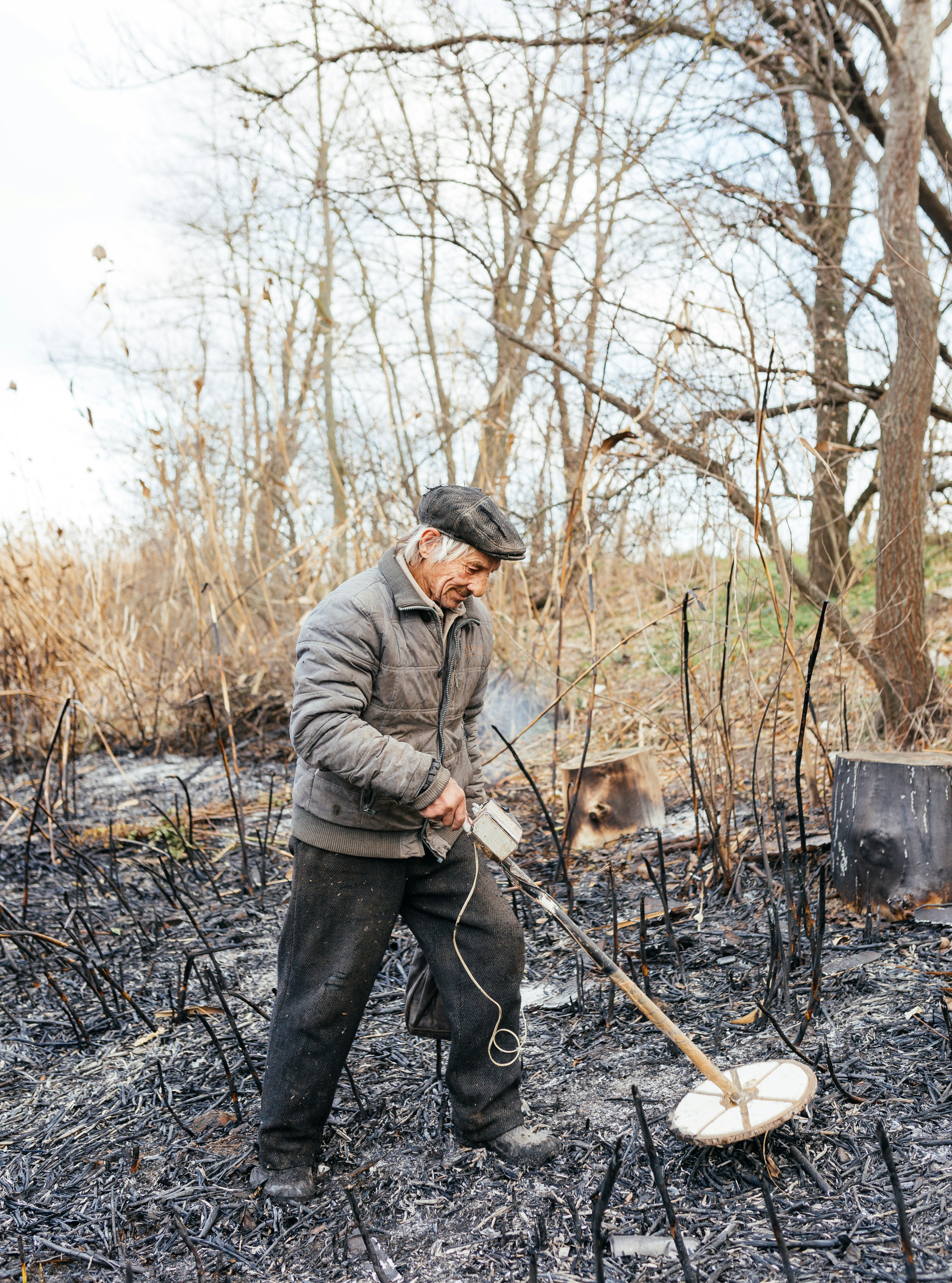 Elderly man looking for treasure with a metal detector