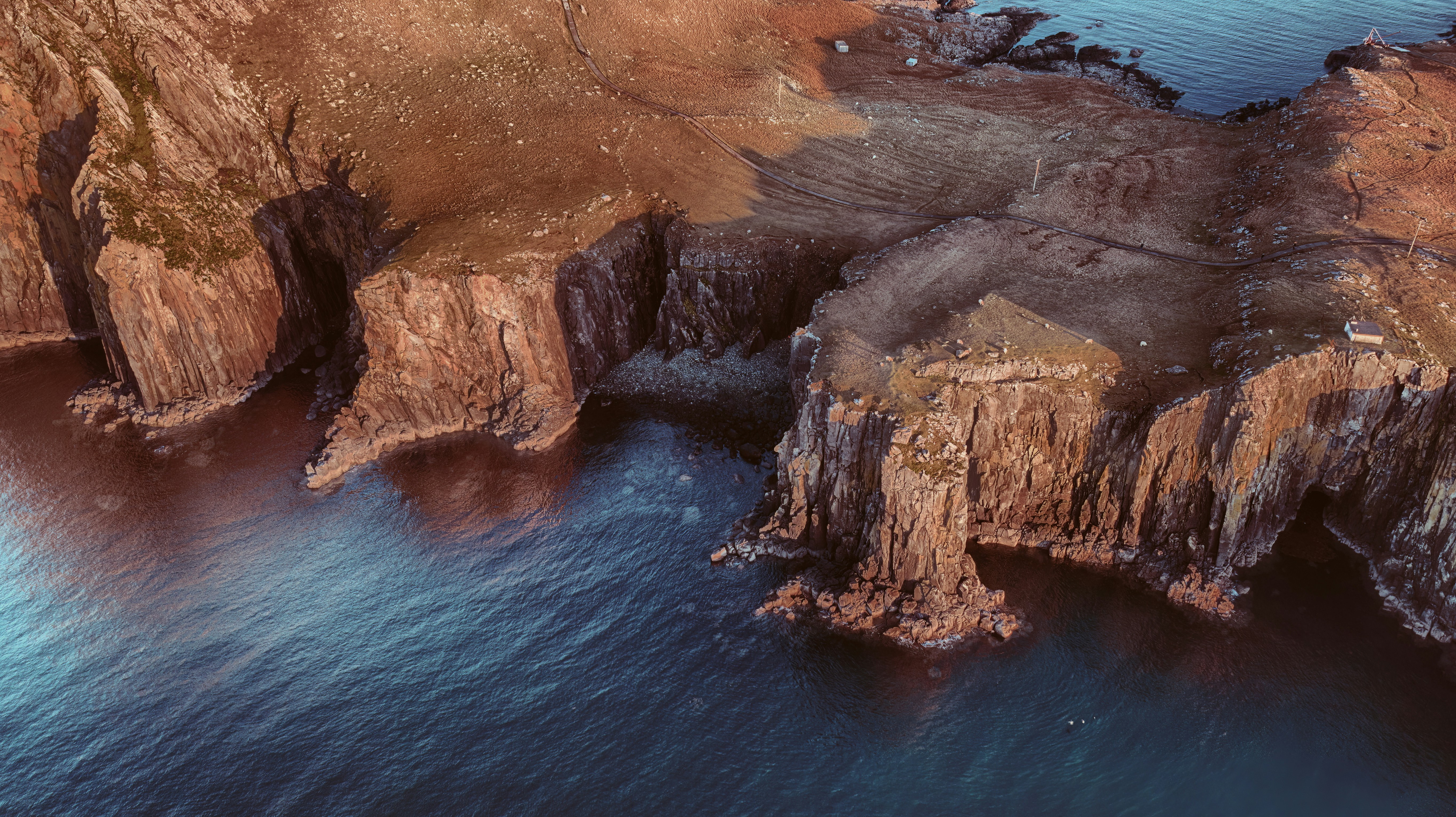 Jagged cliffs meet the tranquil sea, showcasing the intricate patterns of erosion along the coastline.