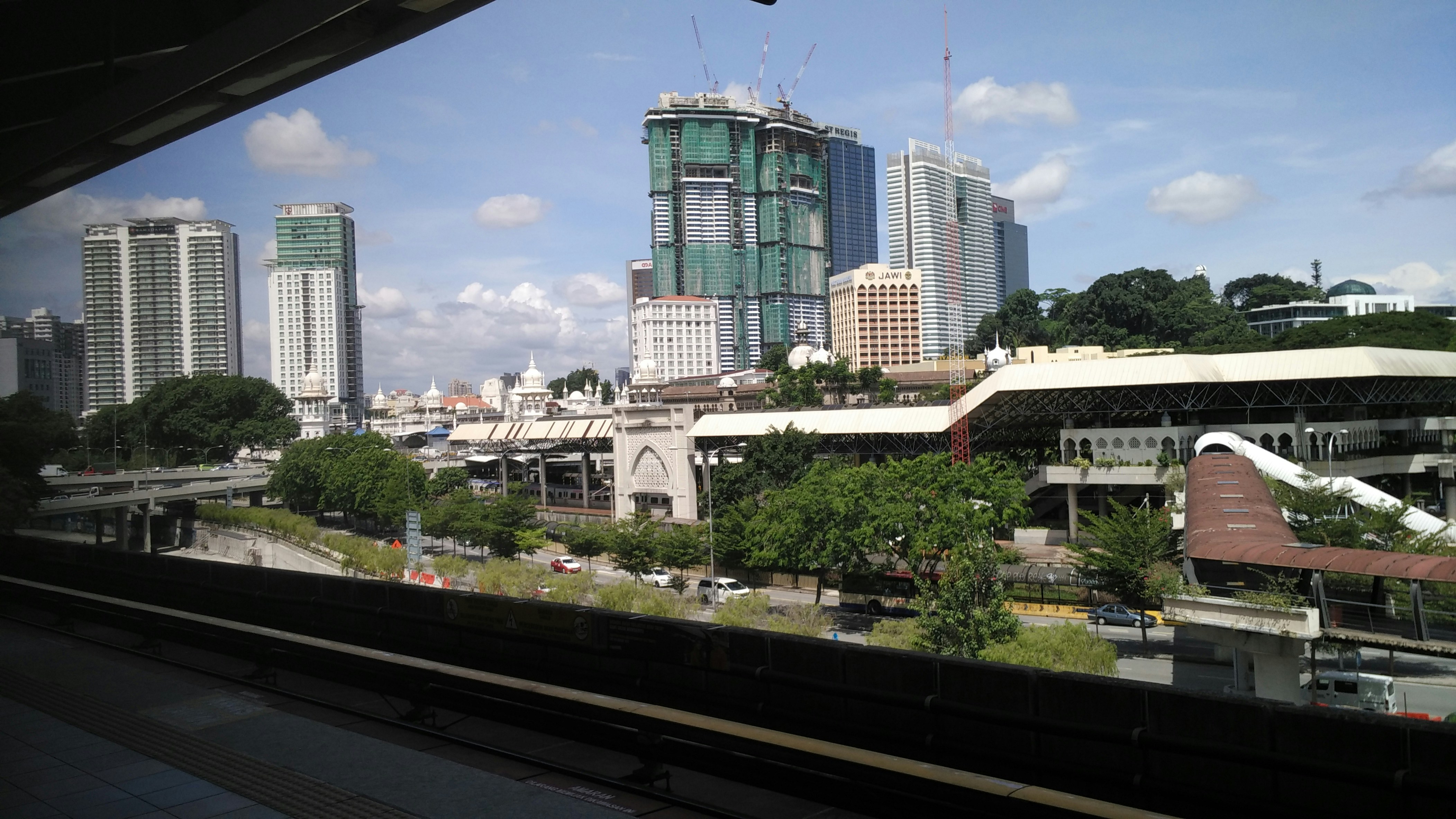 Cityscape featuring a blend of modern skyscrapers and historic architecture under a bright blue sky. The scene captures the dynamic essence of urban life.