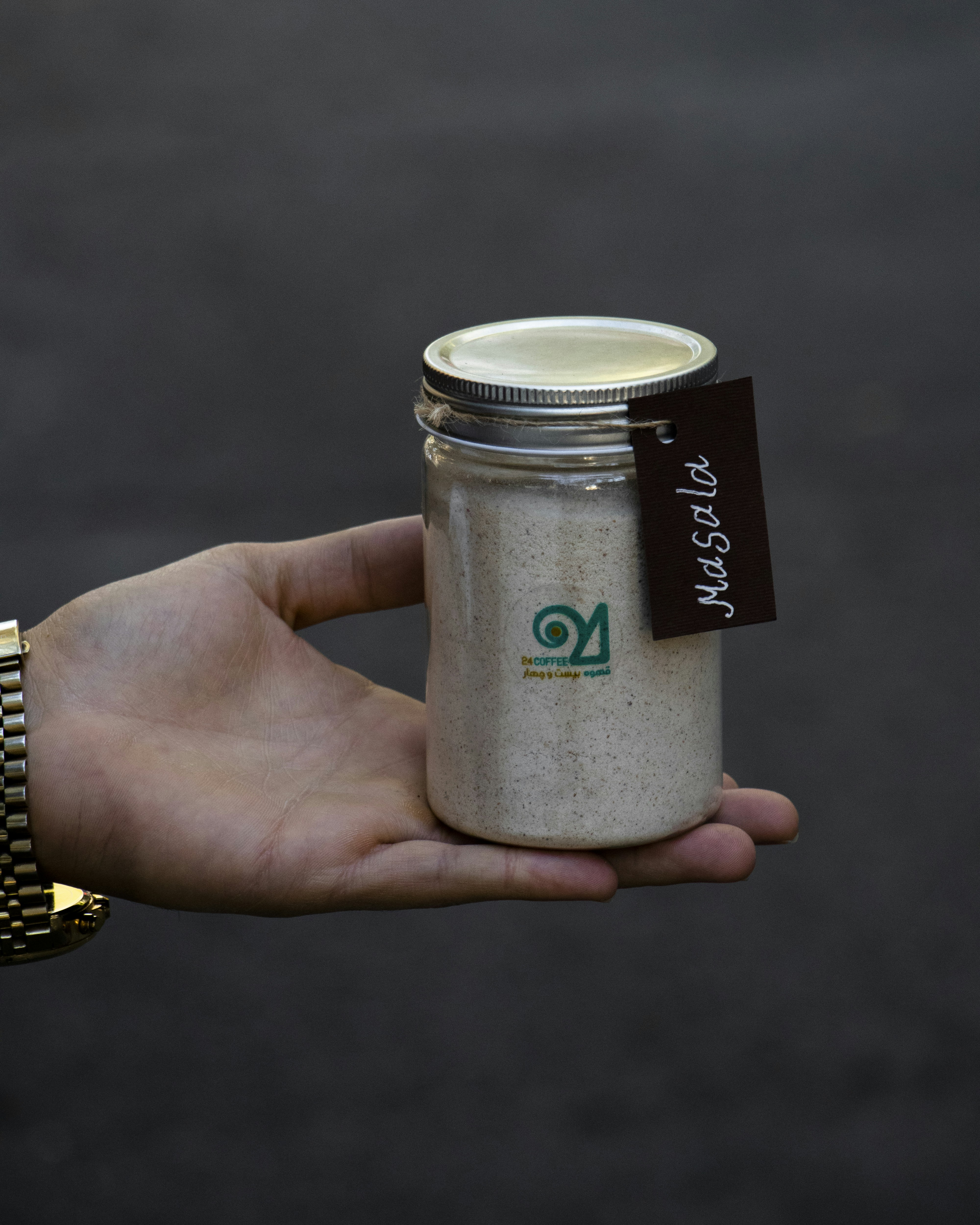 Hand-Held Mason Jar of Creamy Oat Milk Against a Dim Concrete Backdrop