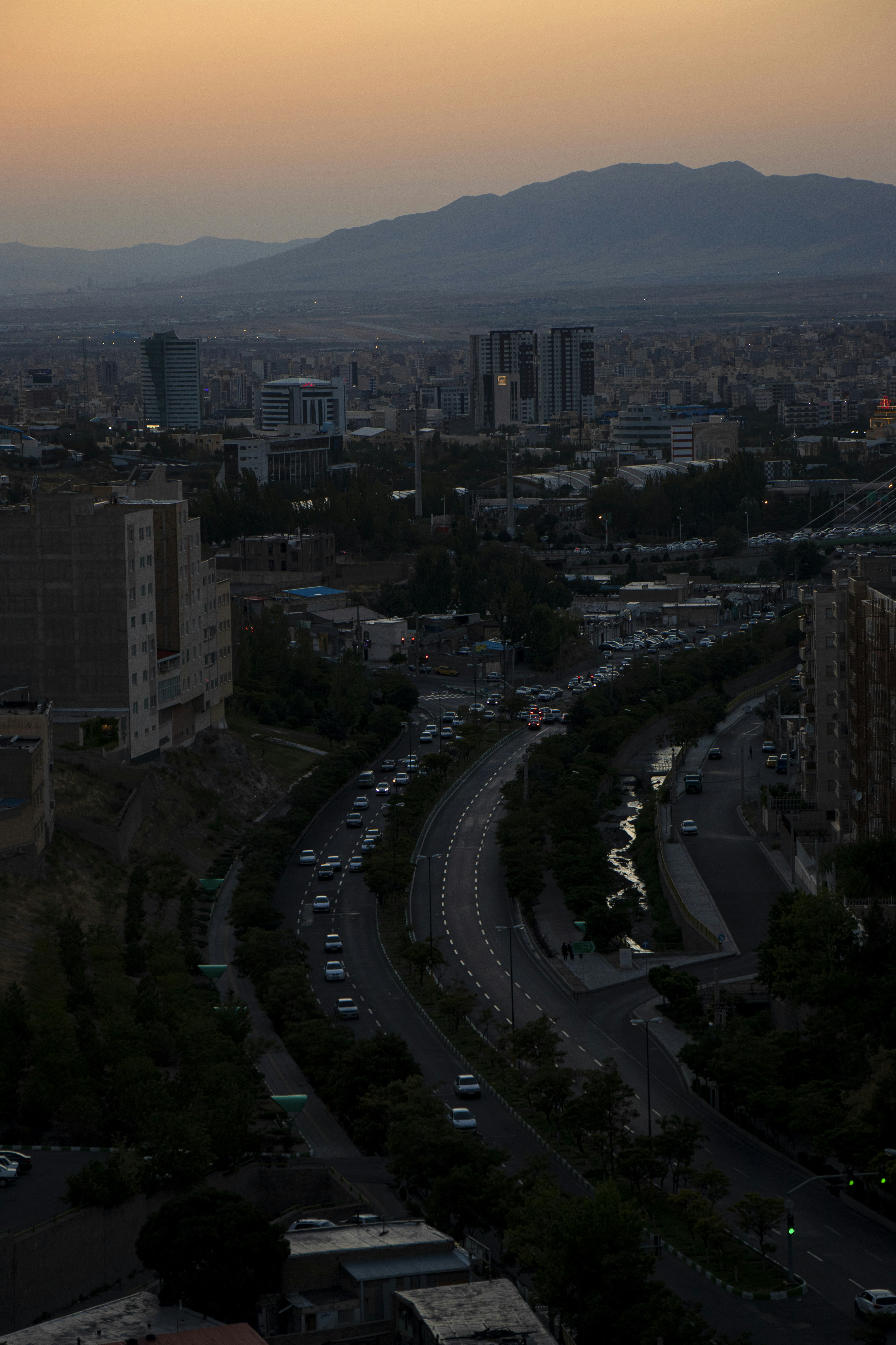 Dusk Over a Winding City: Mountain silhouettes and traffic ribbon