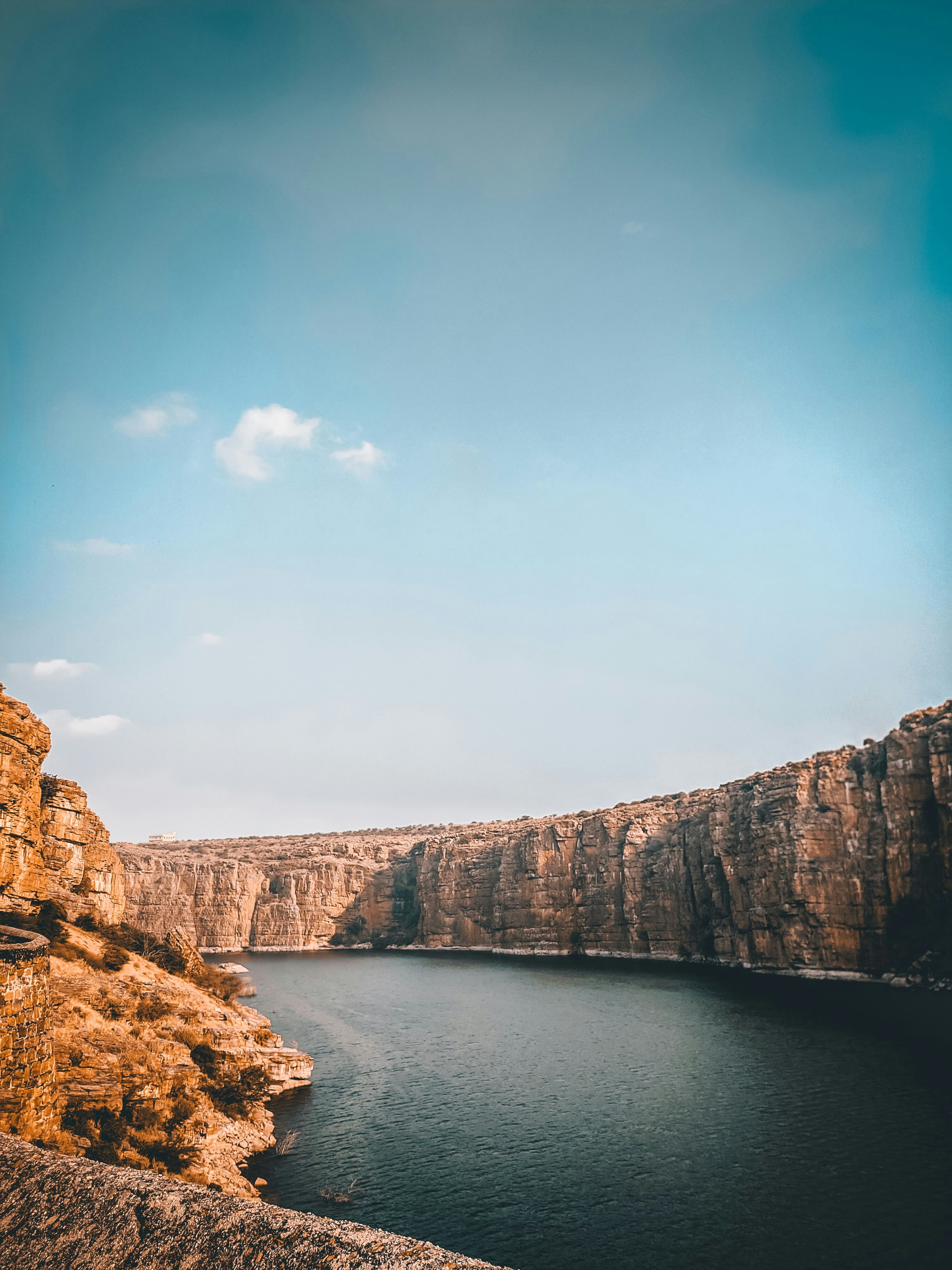 Foto Un cuerpo de agua con un acantilado rocoso y cielo azul – Imagen ...
