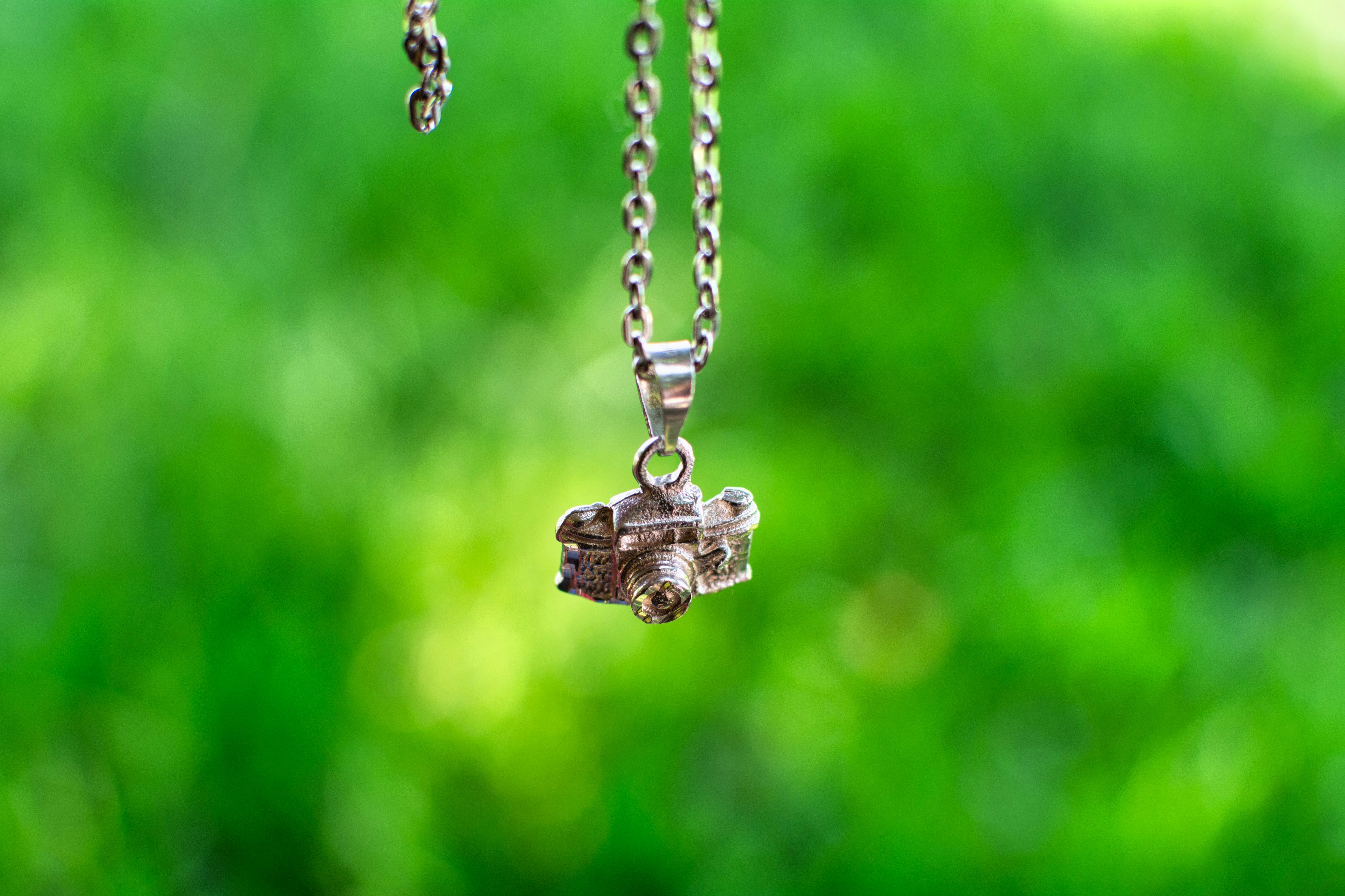 Emerald Bokeh: Tiny Pendant in Sharp Focus Against a Lush Green Backdrop