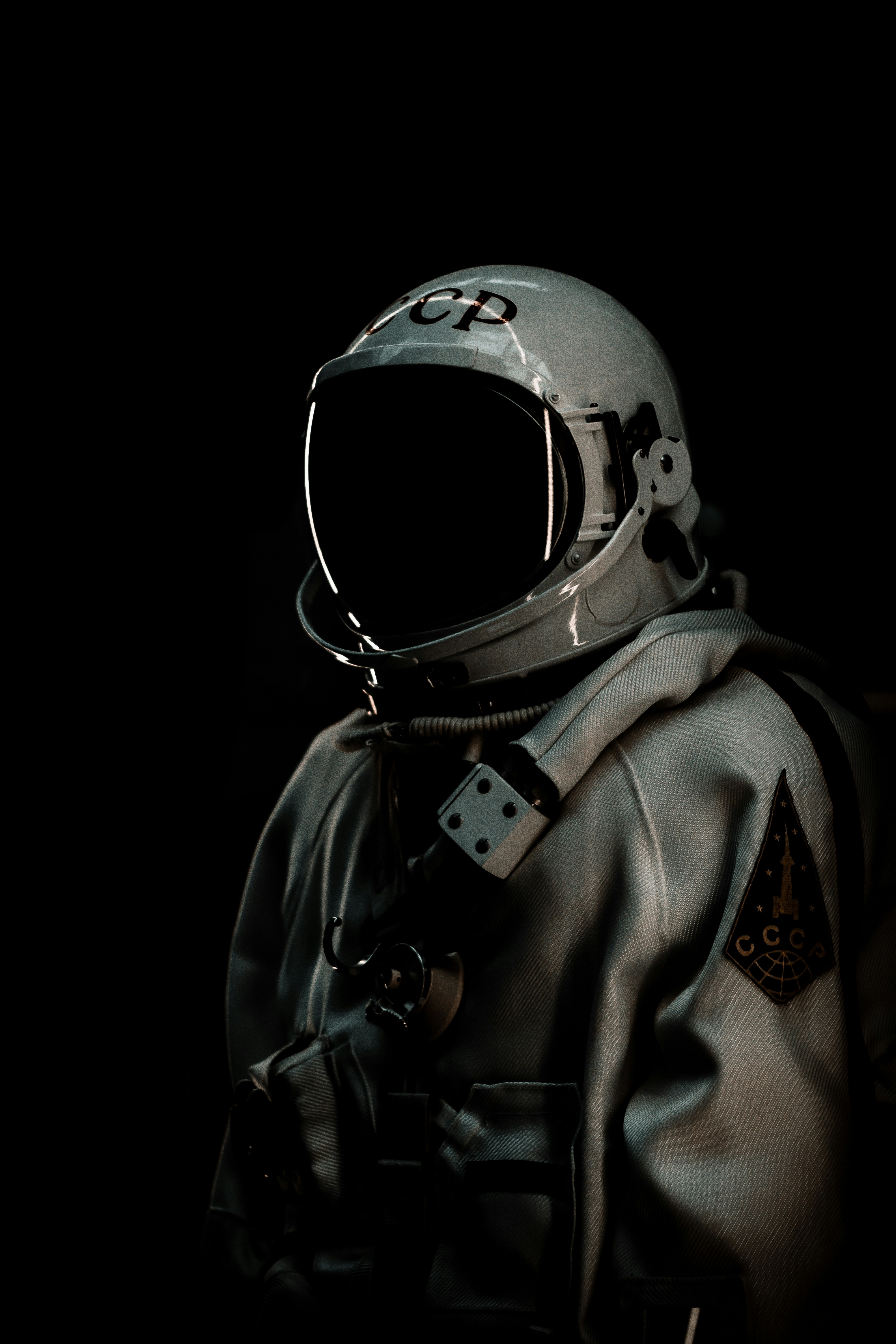 An astronaut in a vintage spacesuit stands against a dark backdrop, embodying the spirit of exploration and adventure. The suit features a distinctive emblem, hinting at a rich history of space travel.