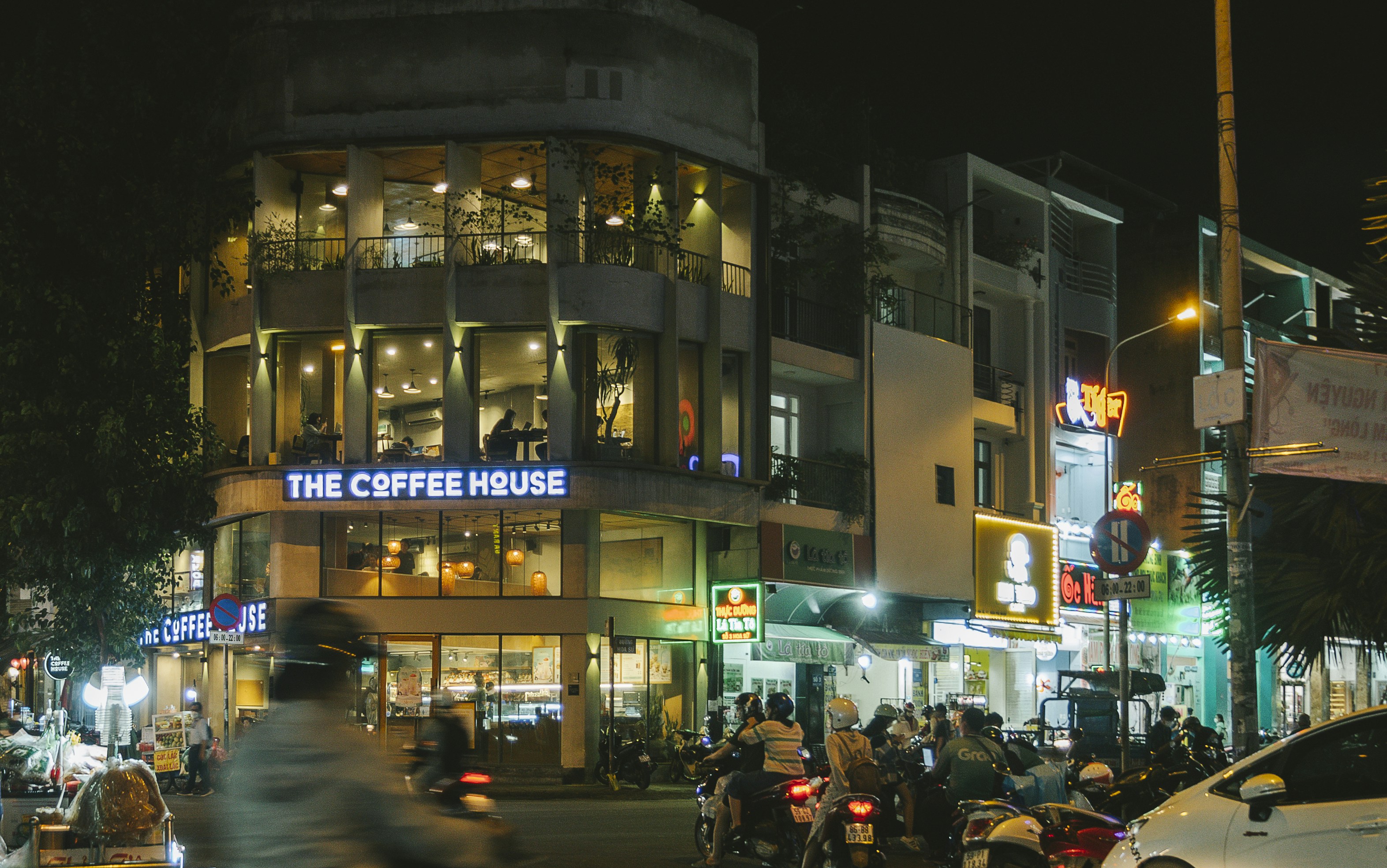 Bustling street scene with The Coffee House illuminated against the night sky in Phu Nhuan.