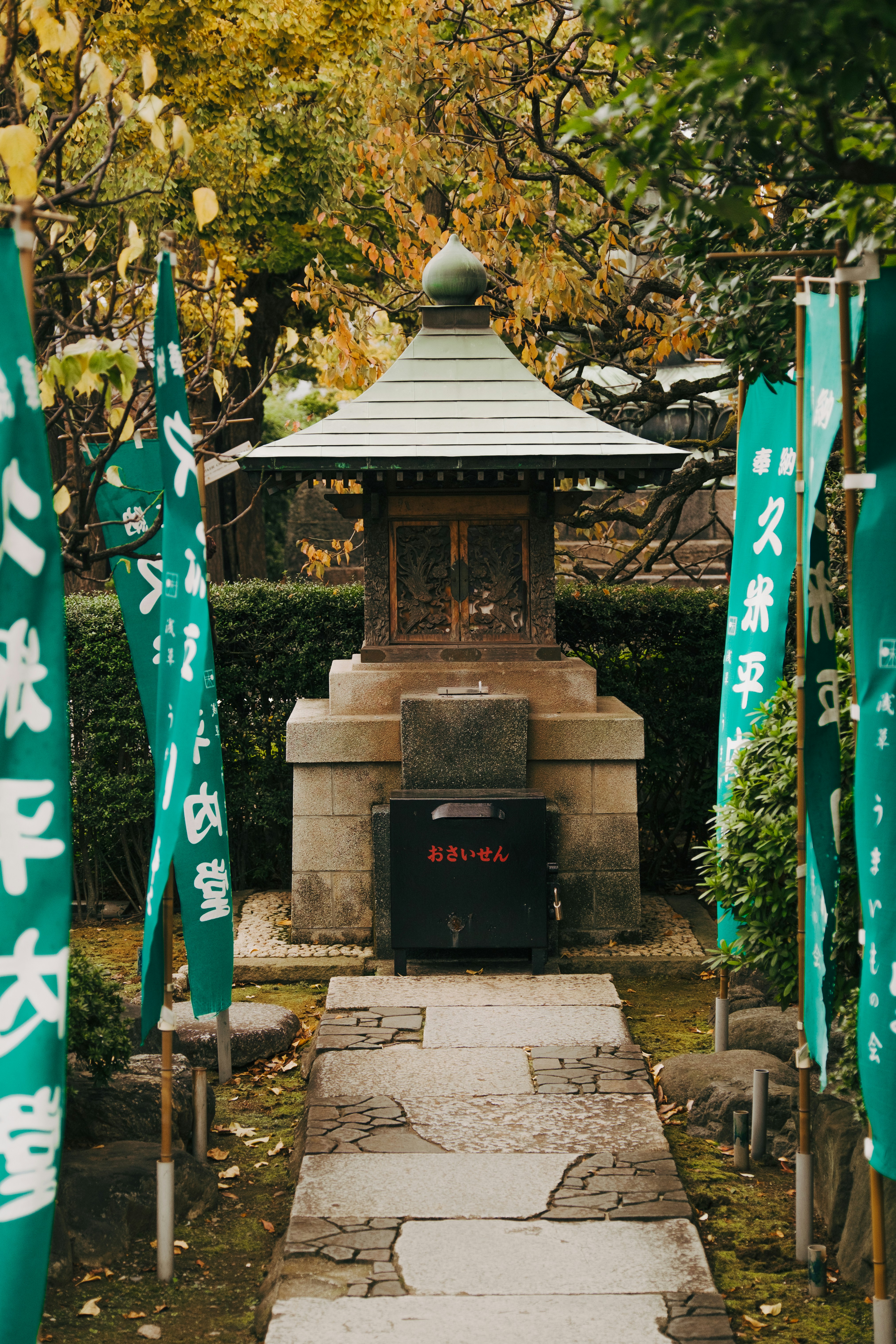 Autumn Shrine Framed by Turquoise Banners Along a Stone Path