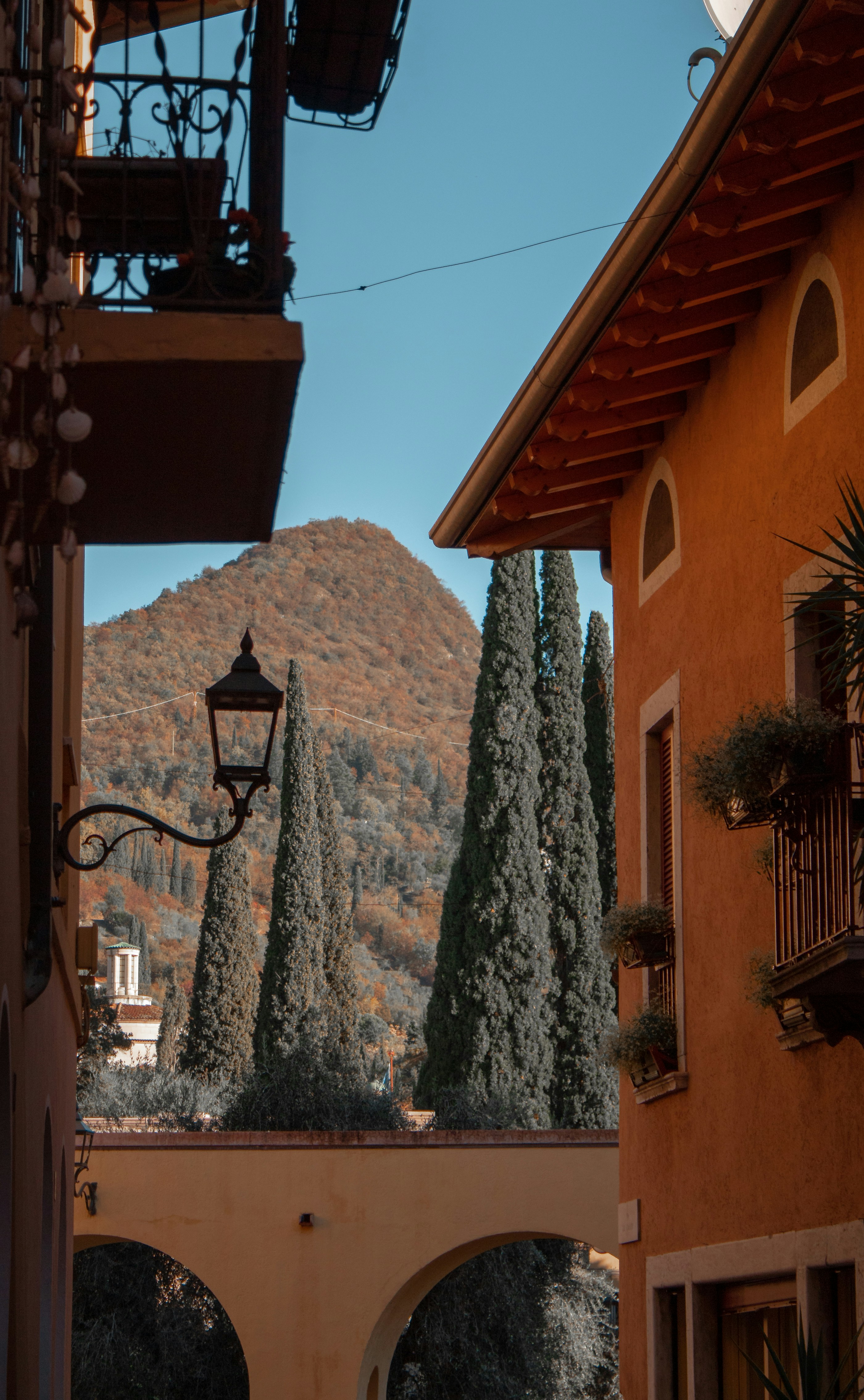 Streets of Salò with orange house and autumn hill in the background