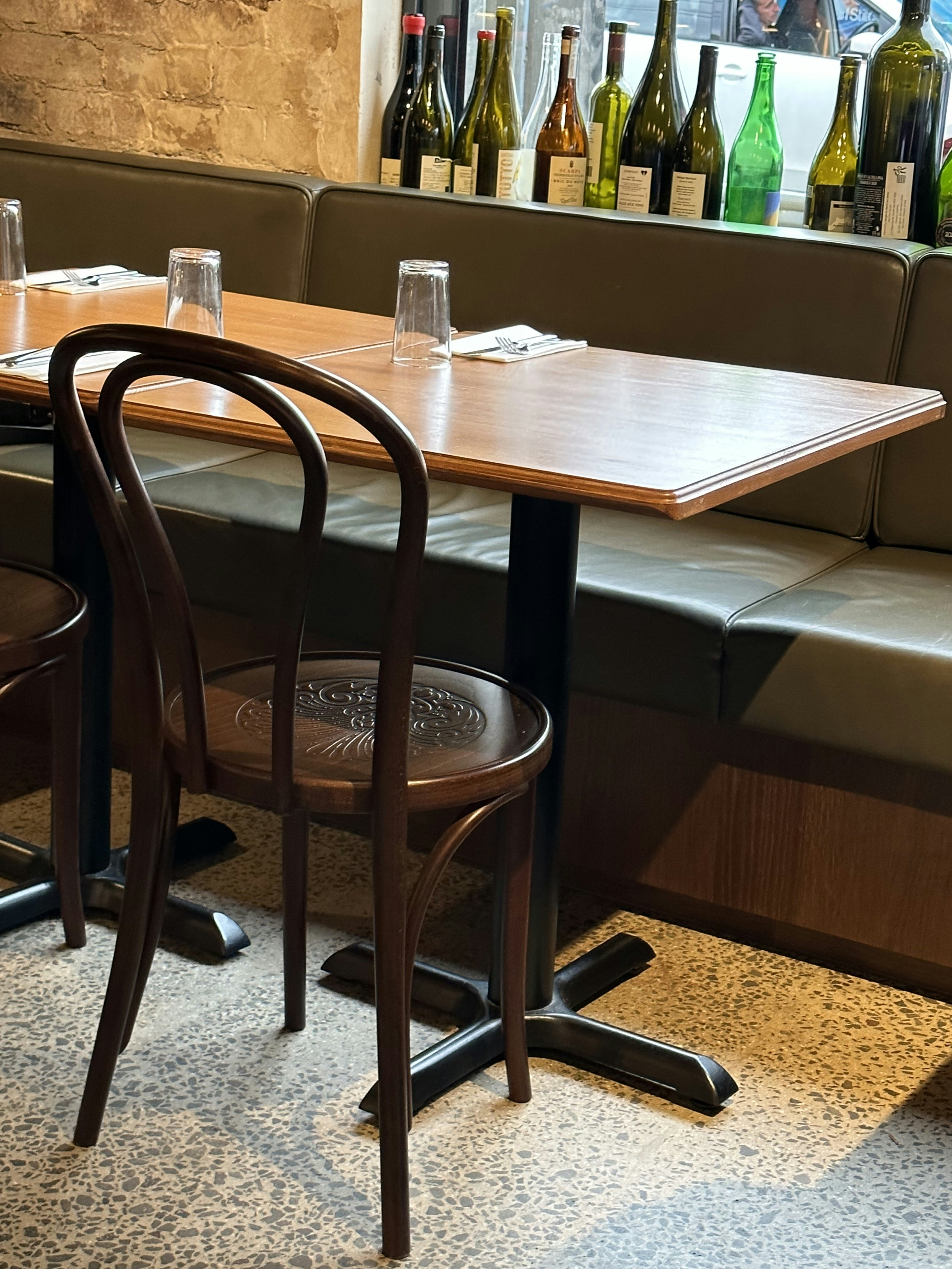 Quiet Bistro Corner: A Wooden Table Framed by Bottles