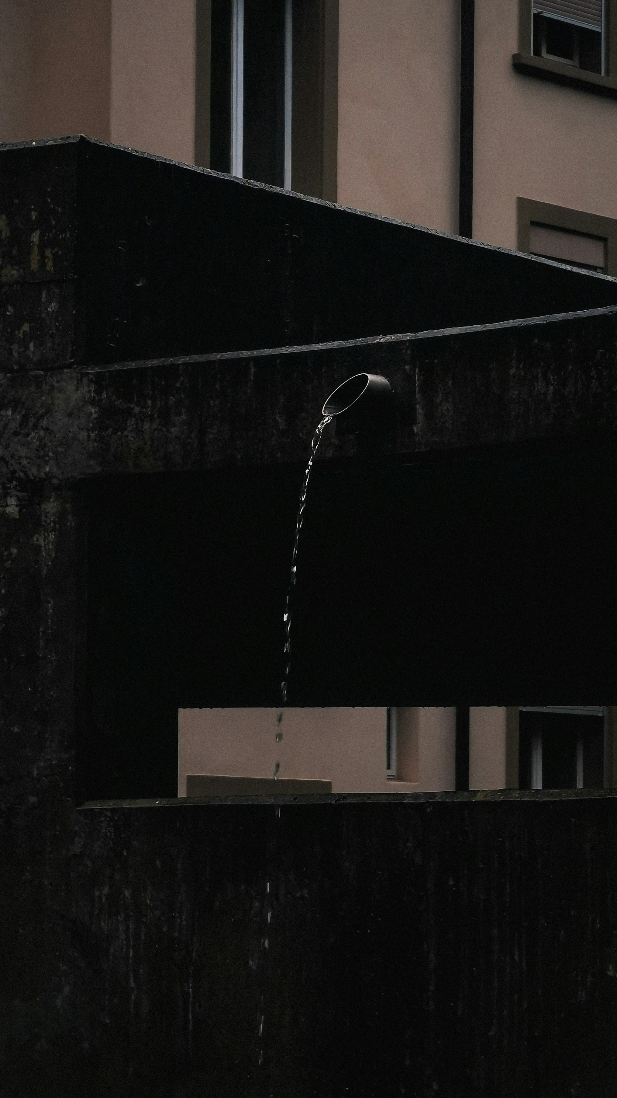 Arc of a Quiet Drip Between Brutalist Walls