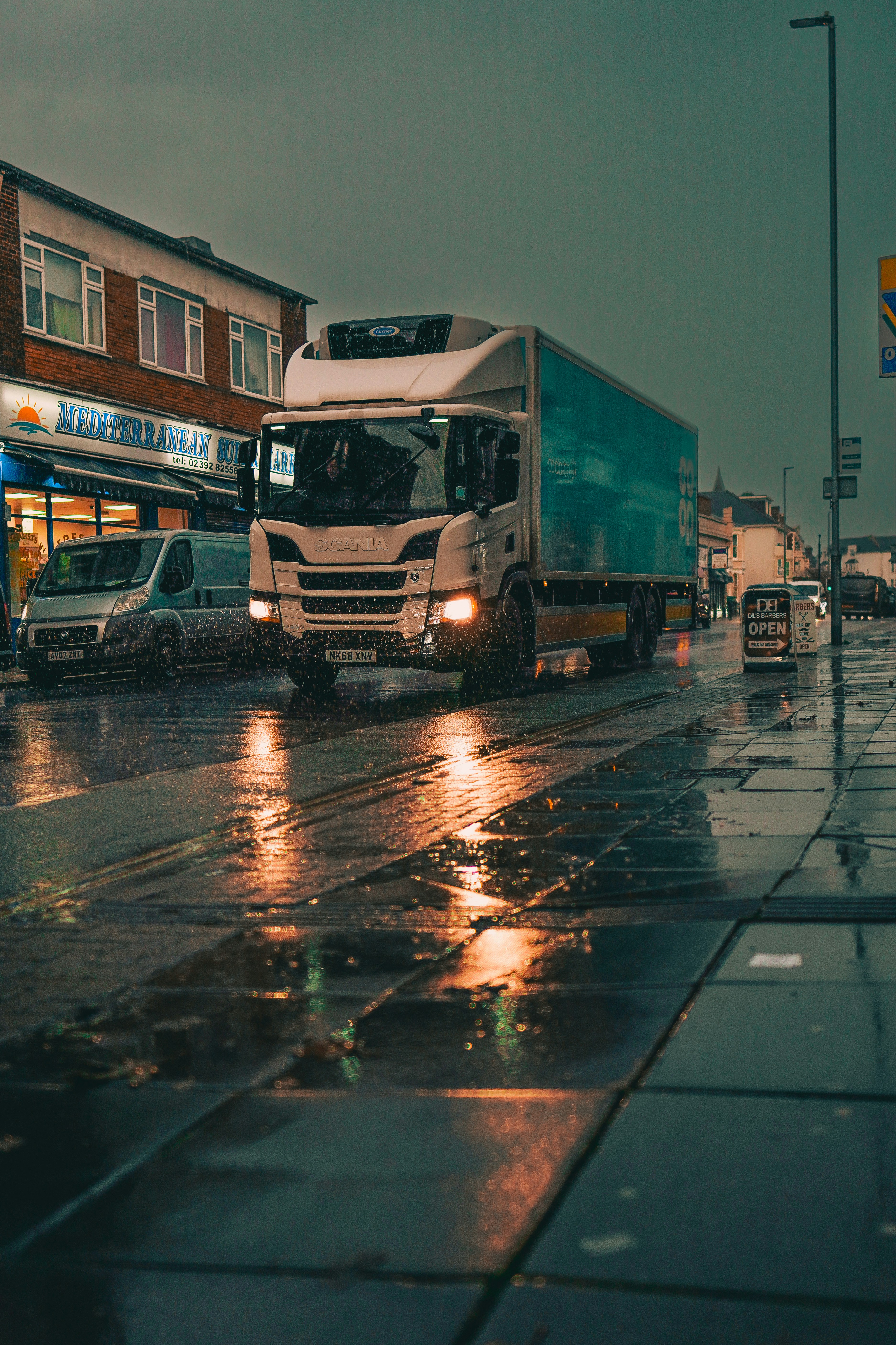 Rain-Soaked Avenue: A Freight Truck Cuts Through Neon-Glazed Reflections