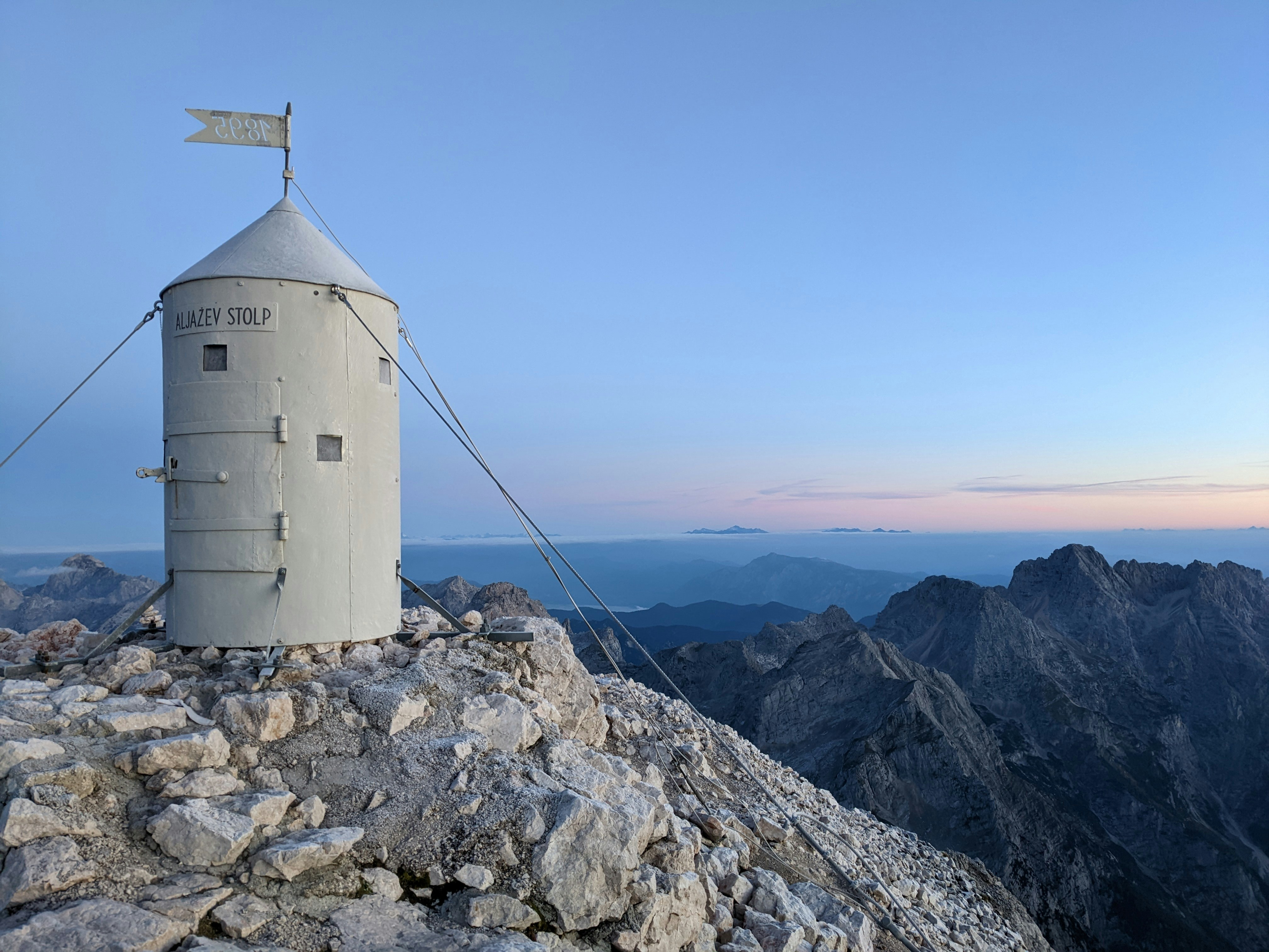 Alpine Sentinel: The Summit Marker Over a Sea of Peaks