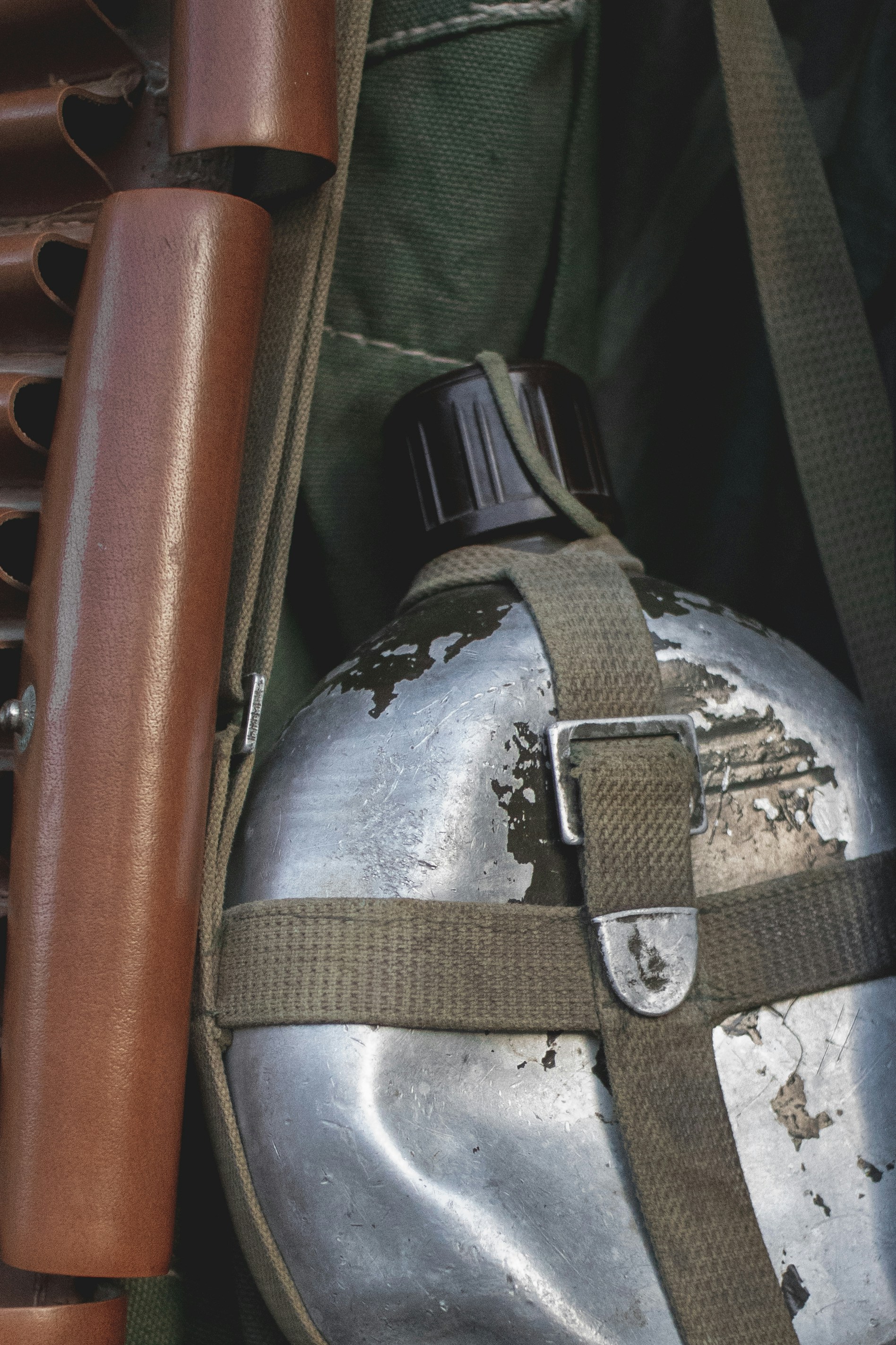 Pinned by Straps: A Weathered Aluminum Canister in a Soldier's Field Kit