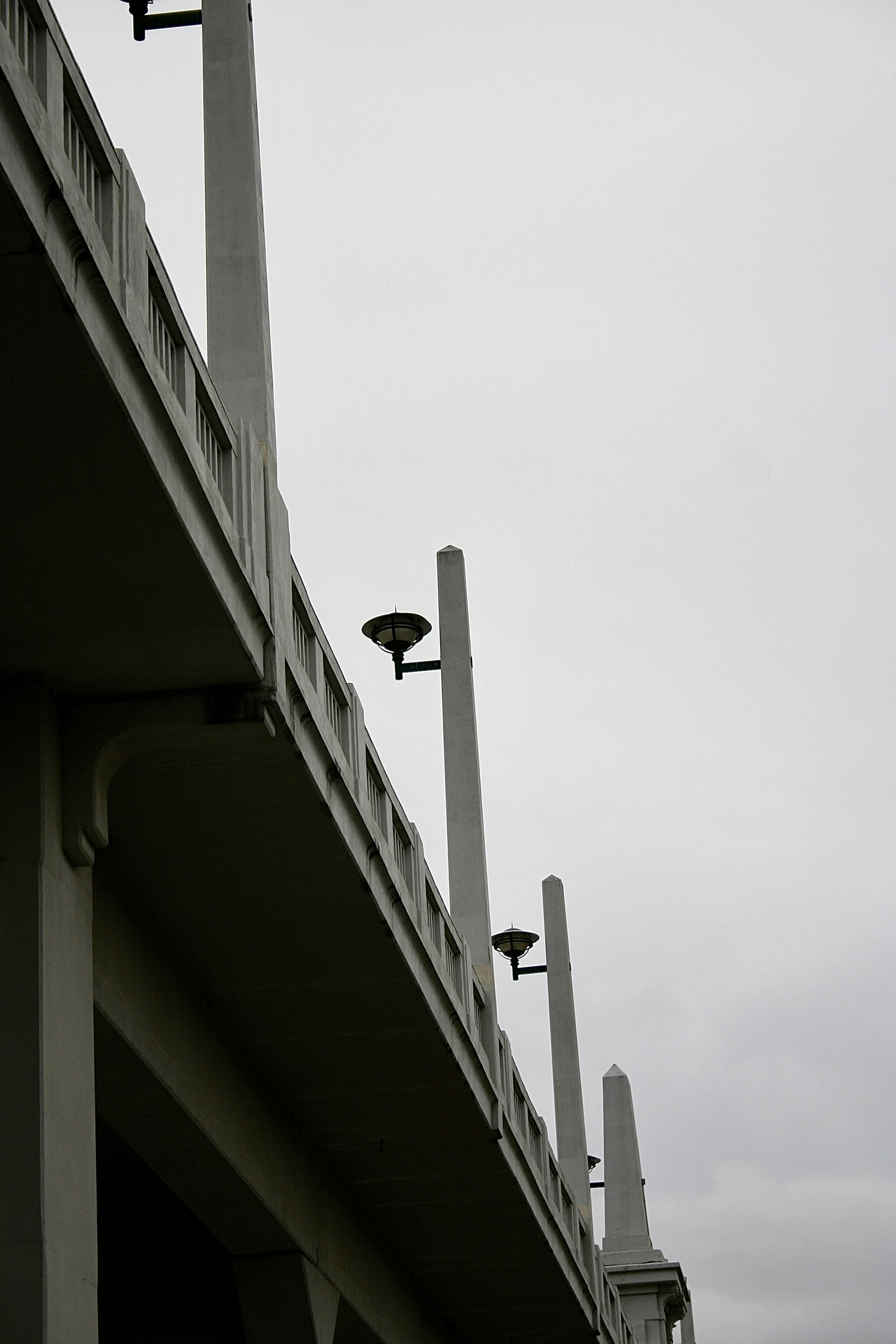 Modern architectural structure featuring tall, slender columns and overhead lighting against a gray sky.