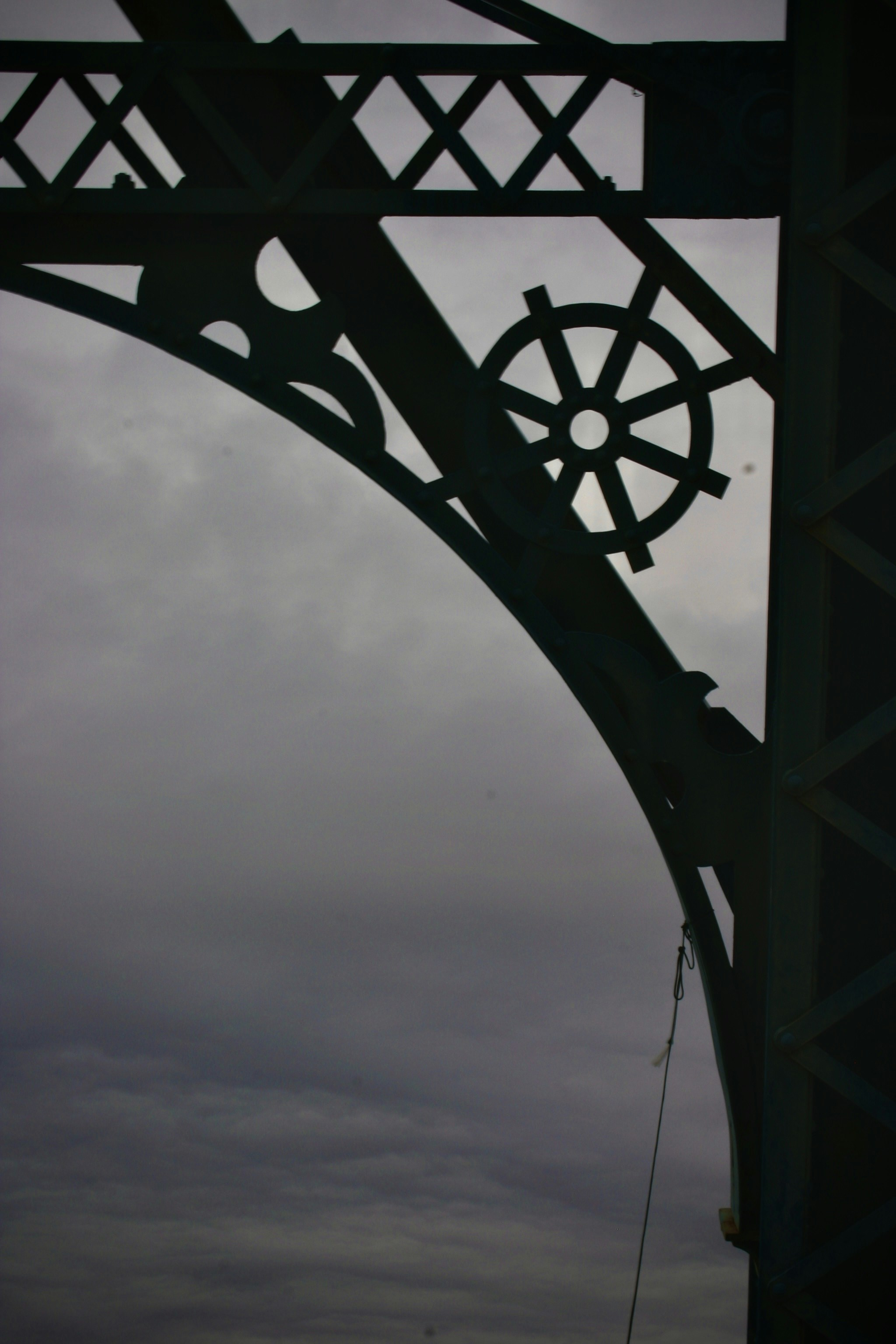 Intricate metalwork of a bridge arch framed against a moody sky, highlighting the beauty of industrial design.