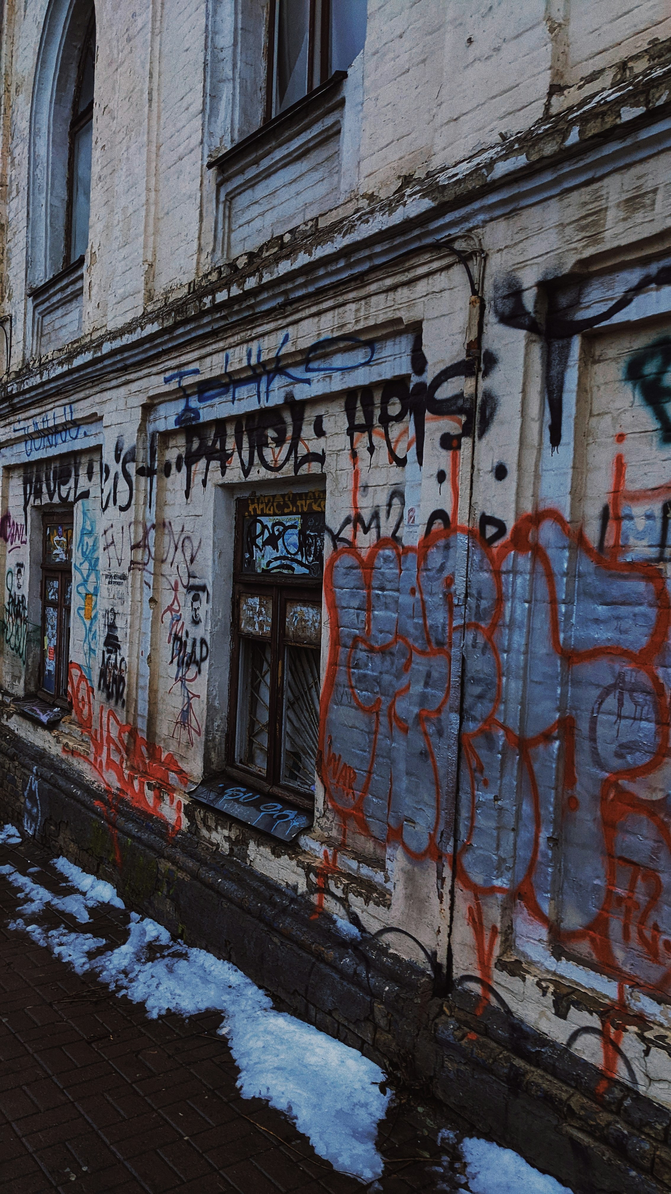 Vibrant graffiti art covering an aged wall, juxtaposed with patches of snow on the ground, showcasing urban decay and creativity.