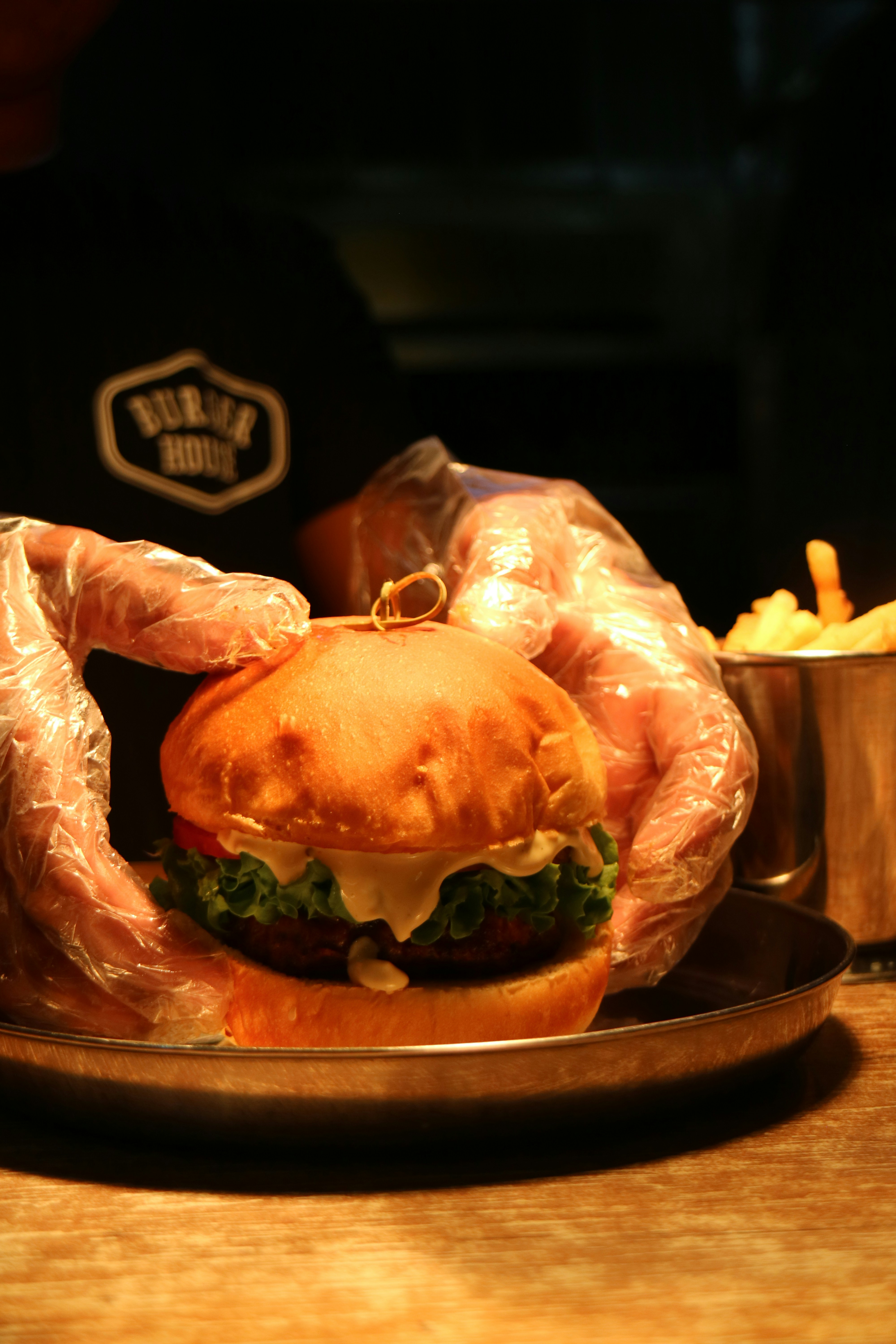 Gloved Hands Crown a Cheeseburger: Warm Kitchen Assembly