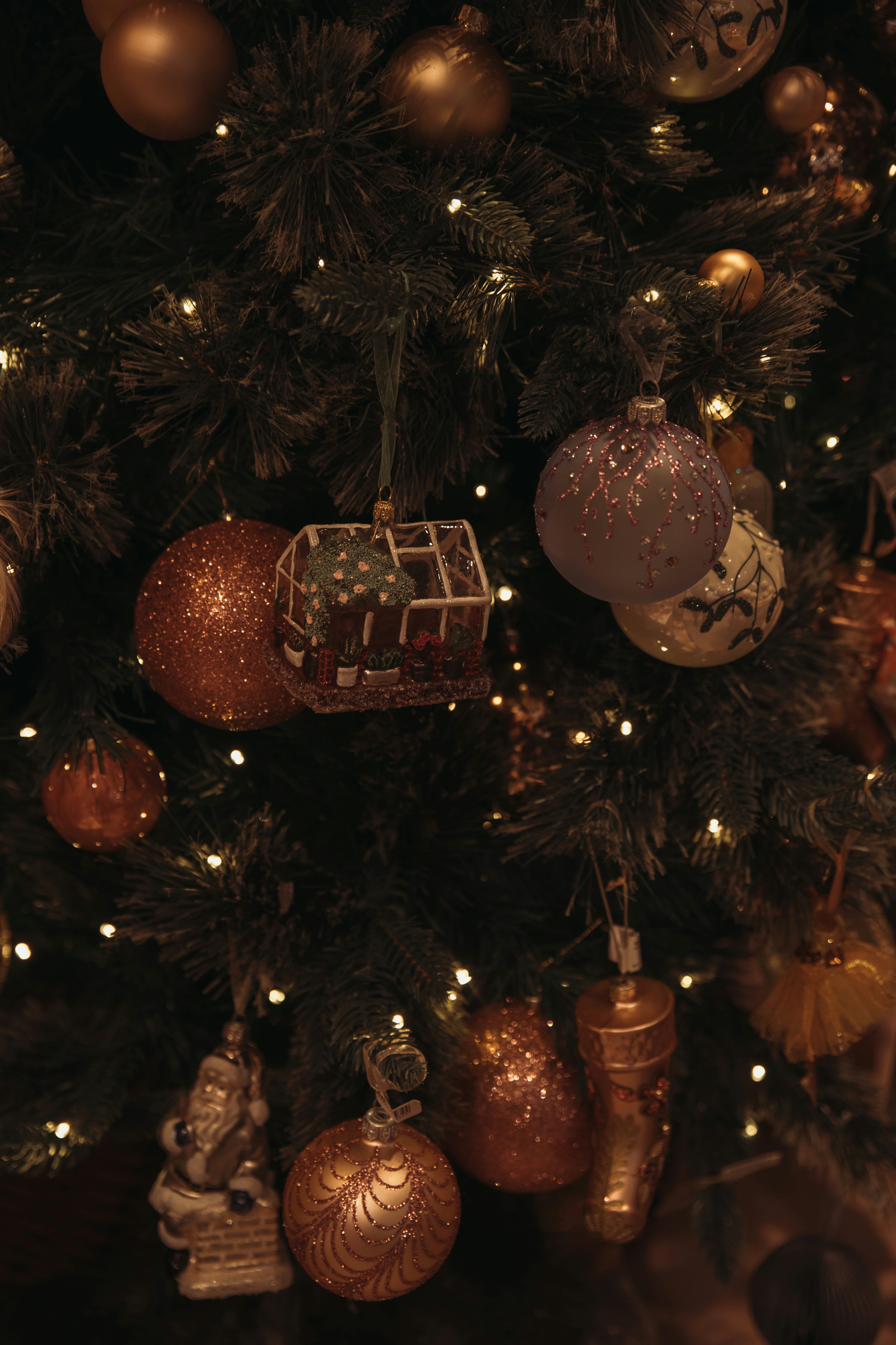 A beautifully decorated Christmas tree adorned with a variety of colorful ornaments and twinkling lights, creating a warm festive atmosphere.