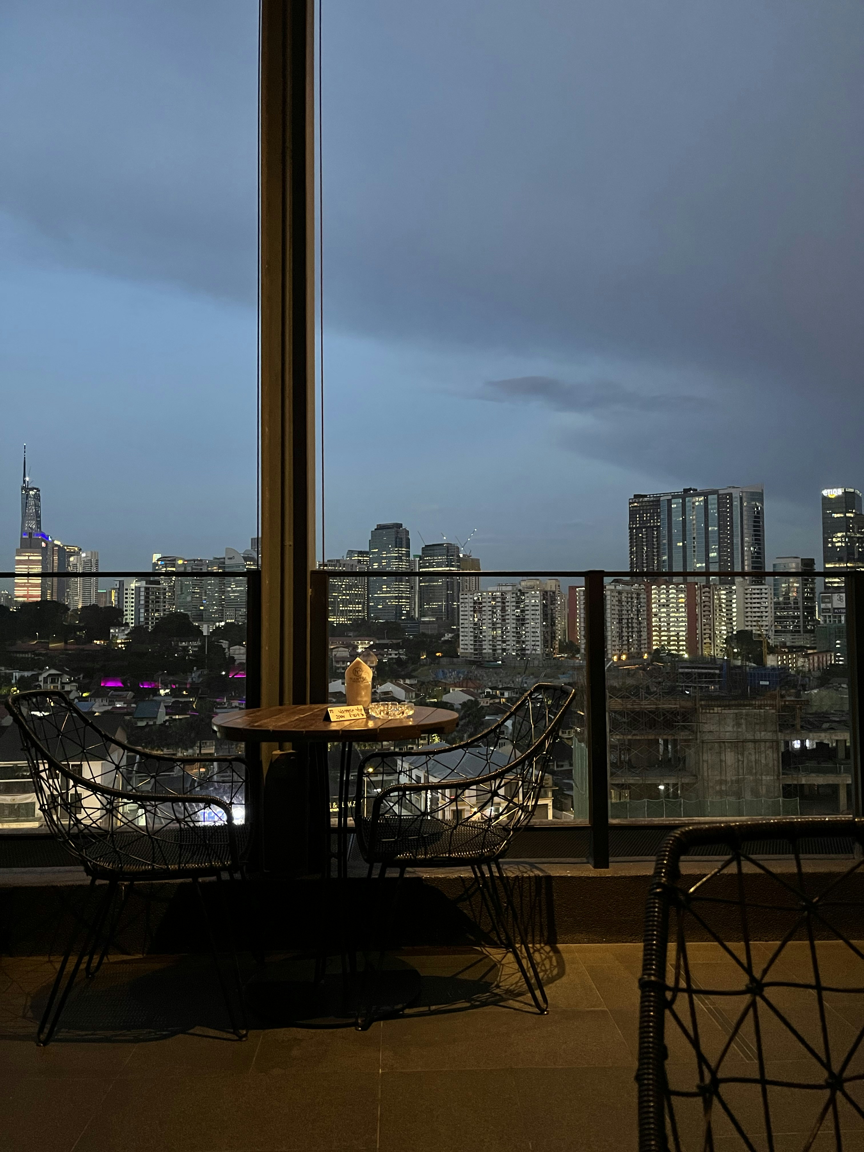 Cozy seating area with a view of a bustling city skyline under twilight. The scene captures a blend of modern architecture and tranquil ambiance.