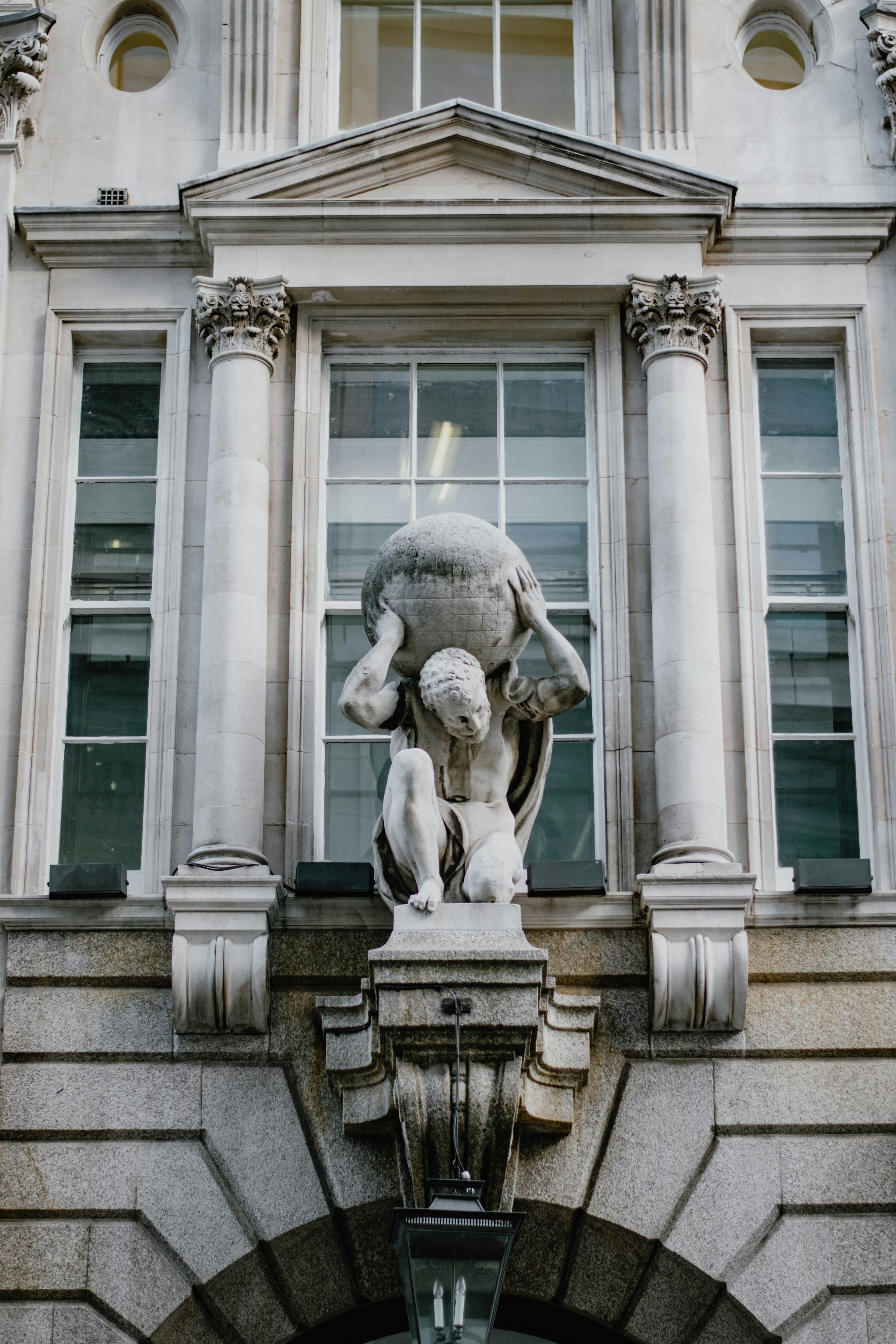 A statue of a person on a pedestal in front of a building photo – Free ...
