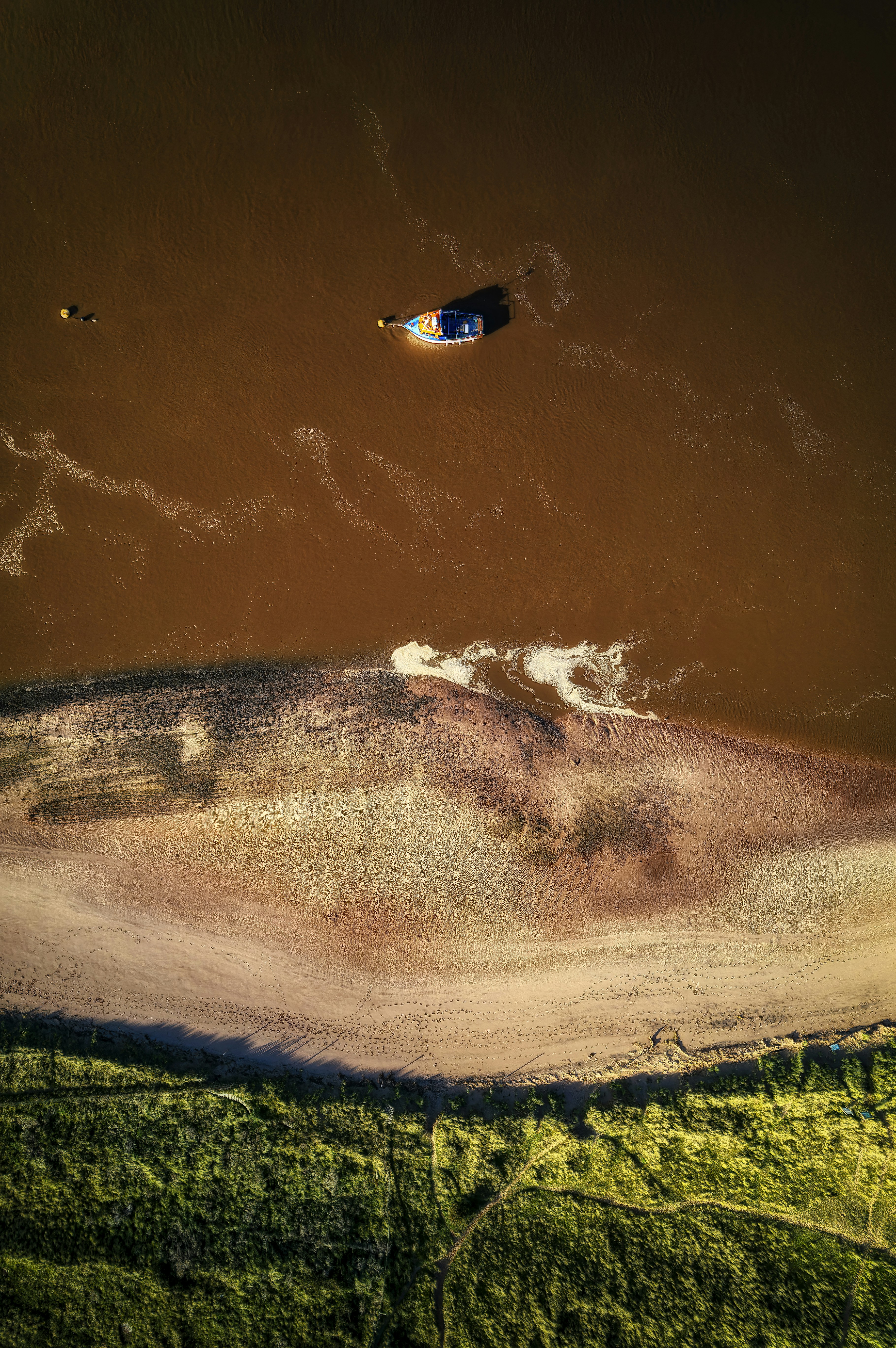 Blue Vessel on Chocolate River: Aerial View of a Curved Shoreline