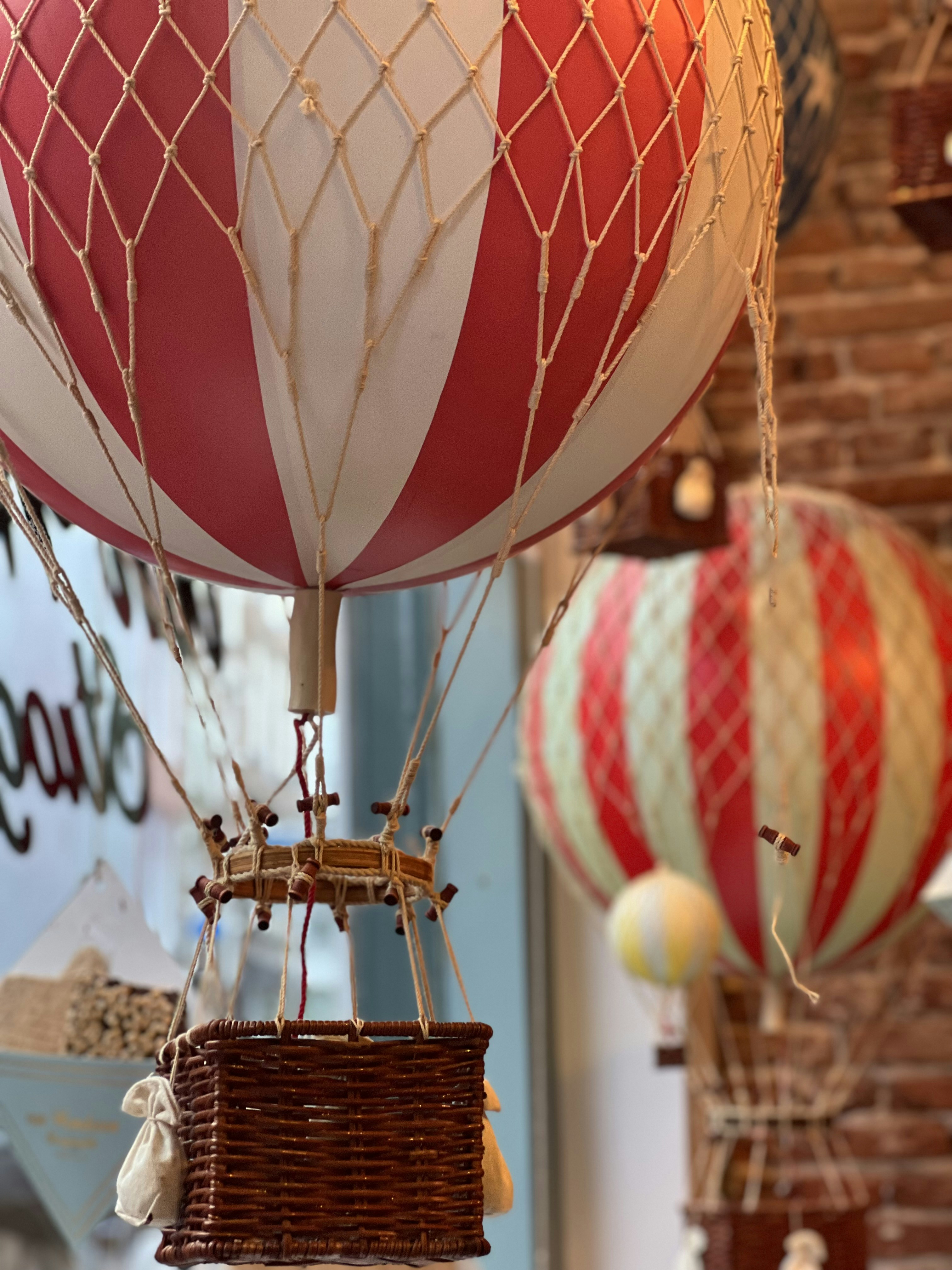 Rattan Drift: A Striped Balloon Carries a Cozy Basket in a Warm Shop