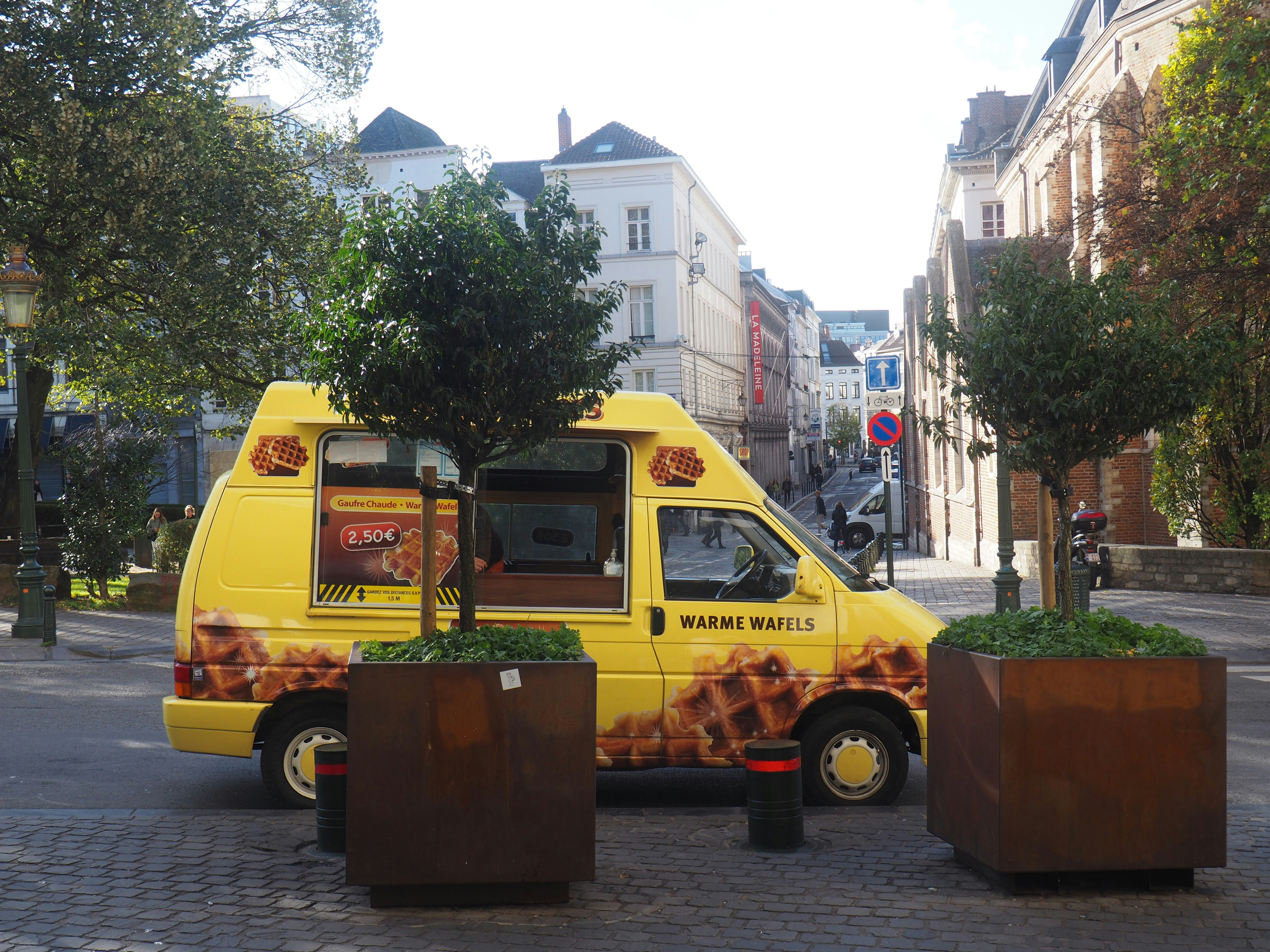 Sunlit Yellow Waffle Van on a Quiet European Street