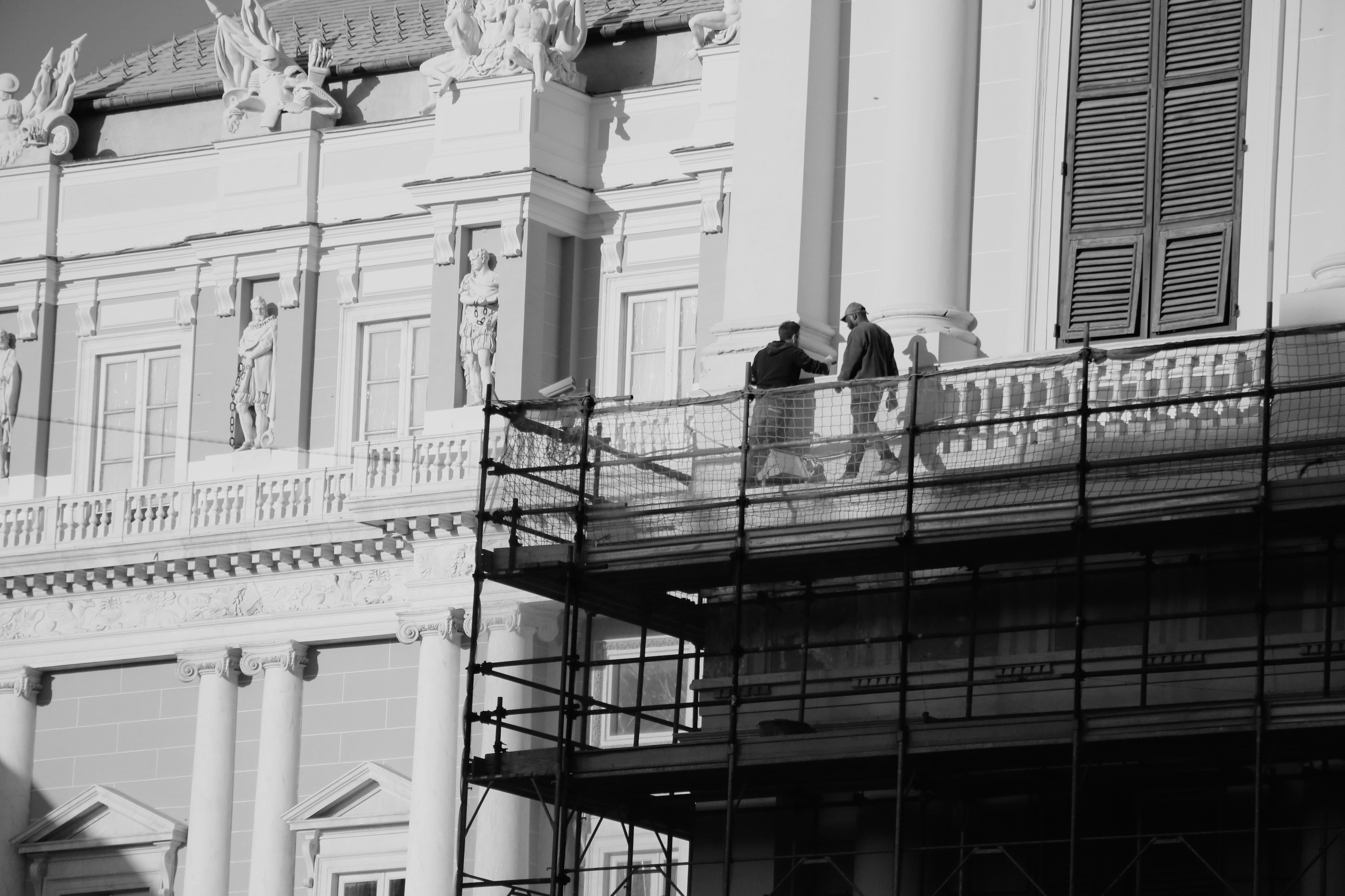 Bridge of Stillness: Two Figures on a Scaffolded Facade