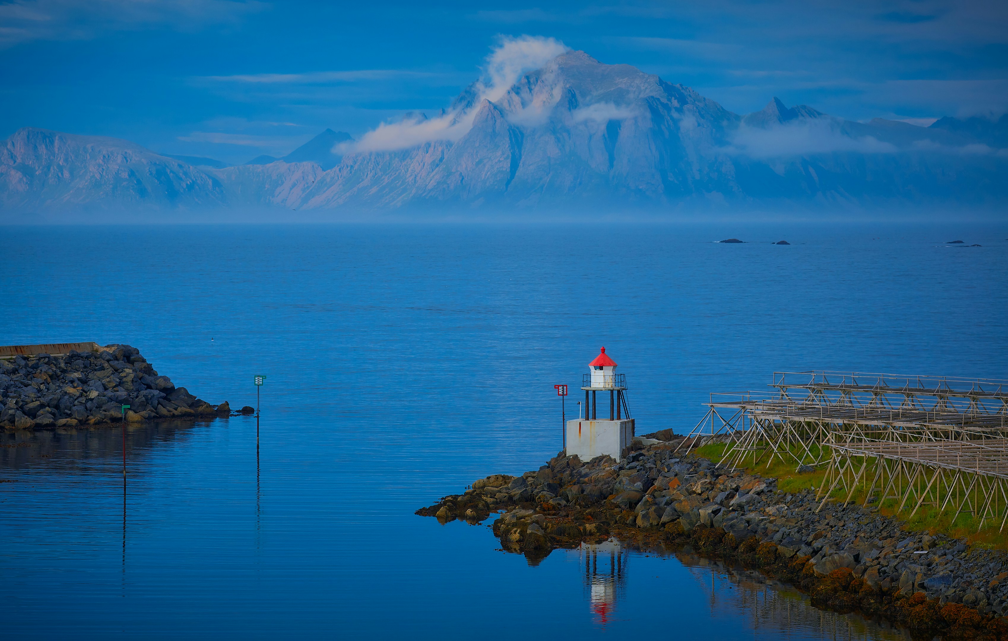 Beacon at the edge of an ice-blue sea under frosted, distant peaks
