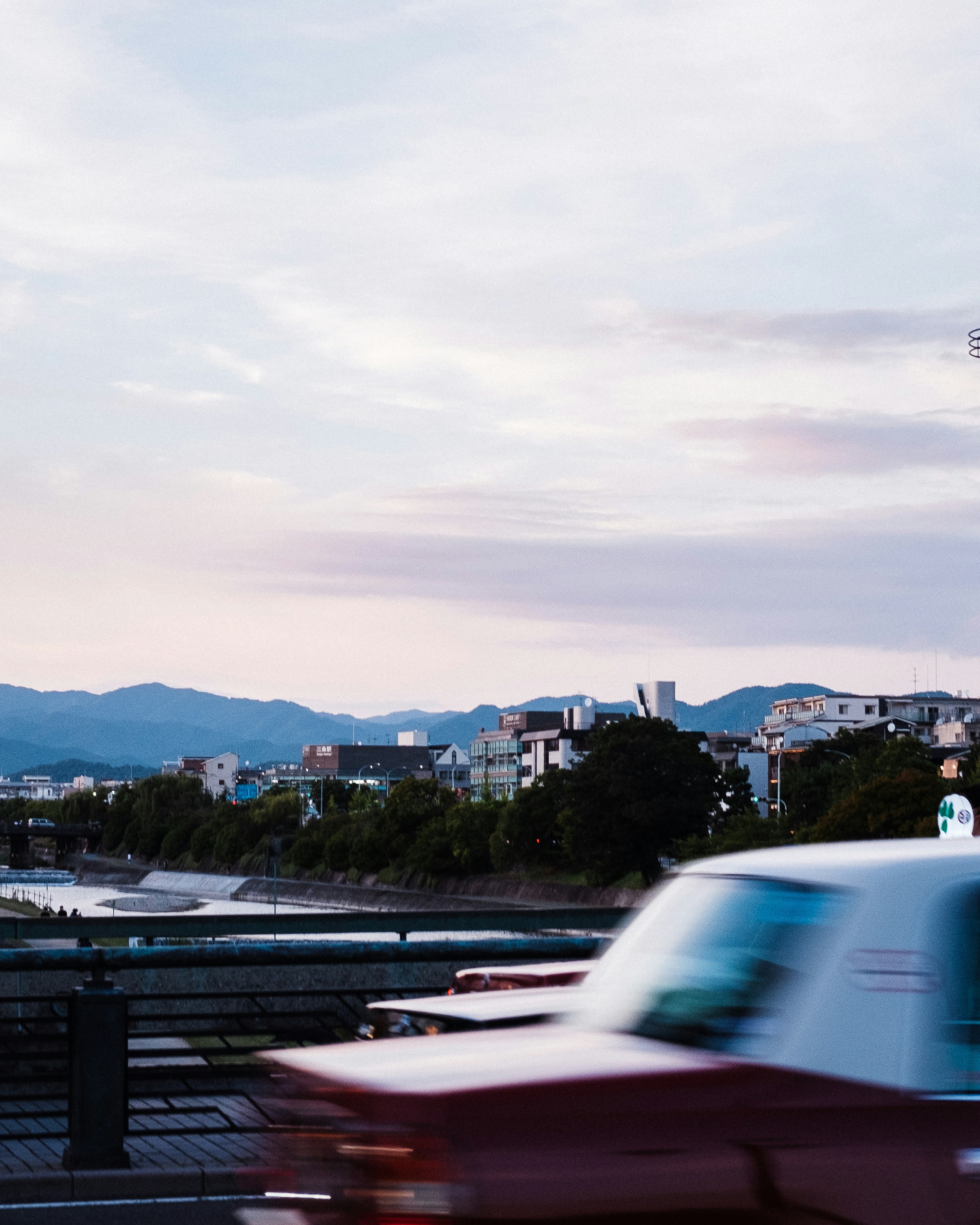 Dusklight over the riverfront: a commuter bus blurs past a calm cityscape
