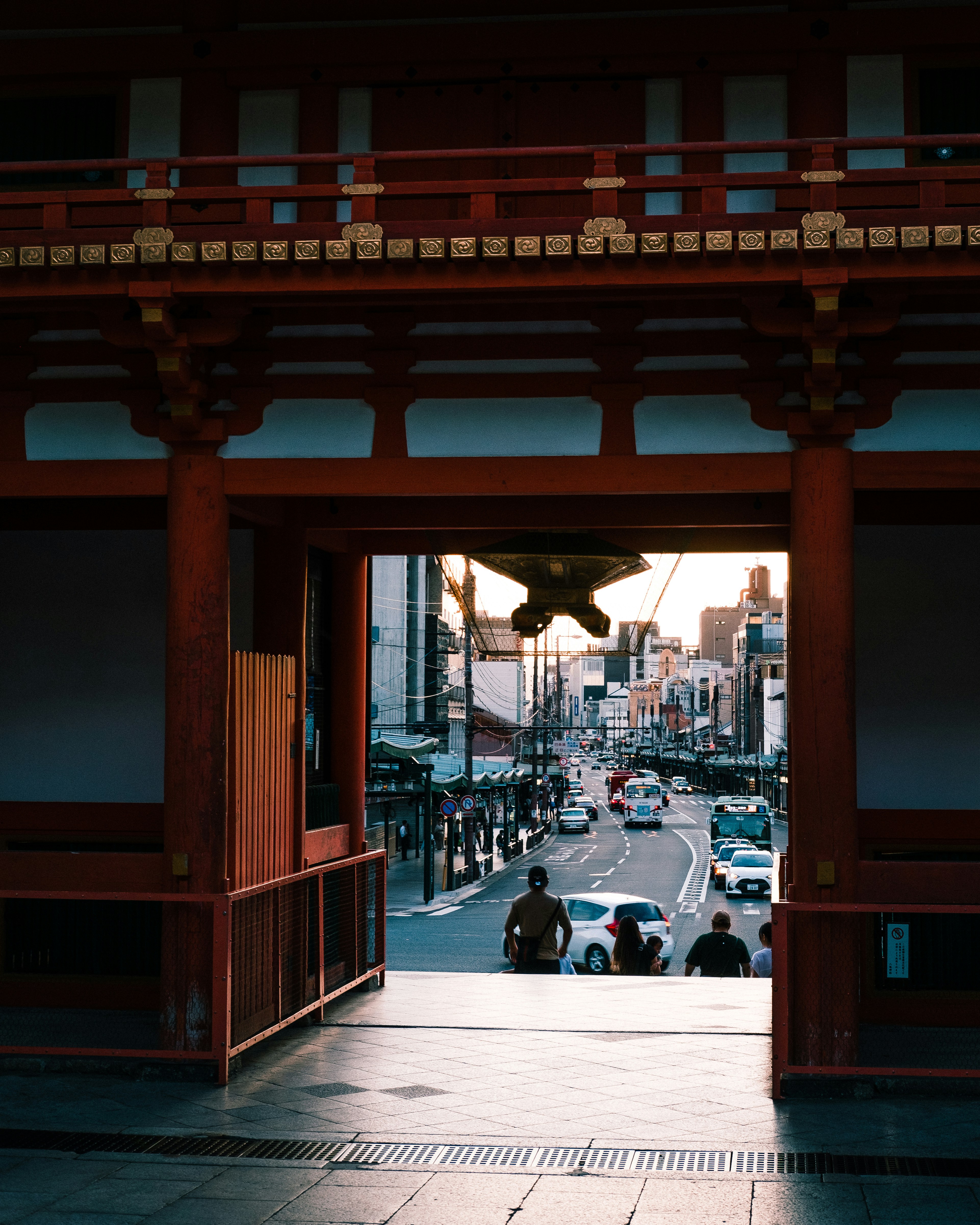 A vibrant urban scene framed by traditional architecture, showcasing a bustling street at sunset.