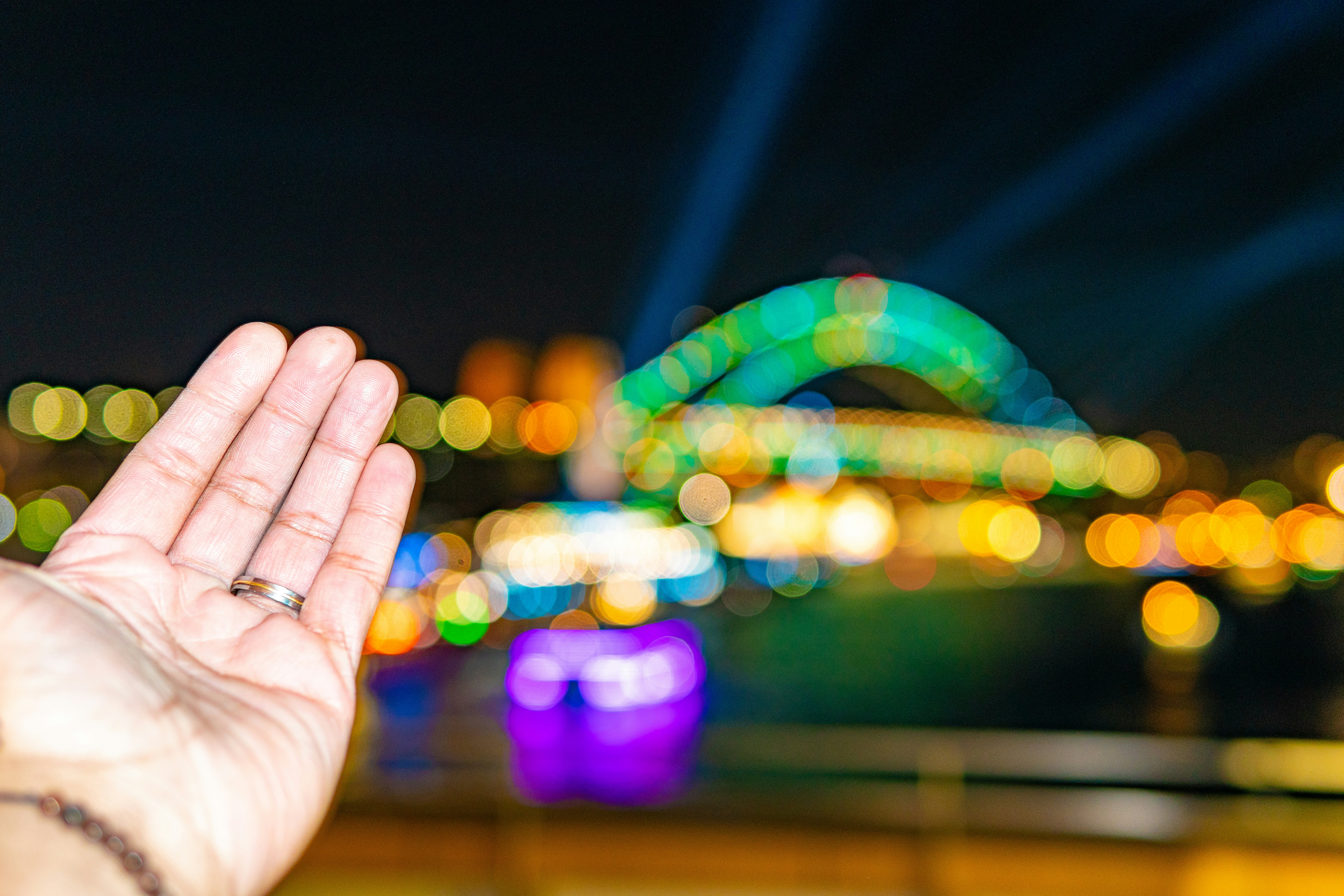 Handshake Against Neon Bokeh: A Nighttime Waterfront Moment