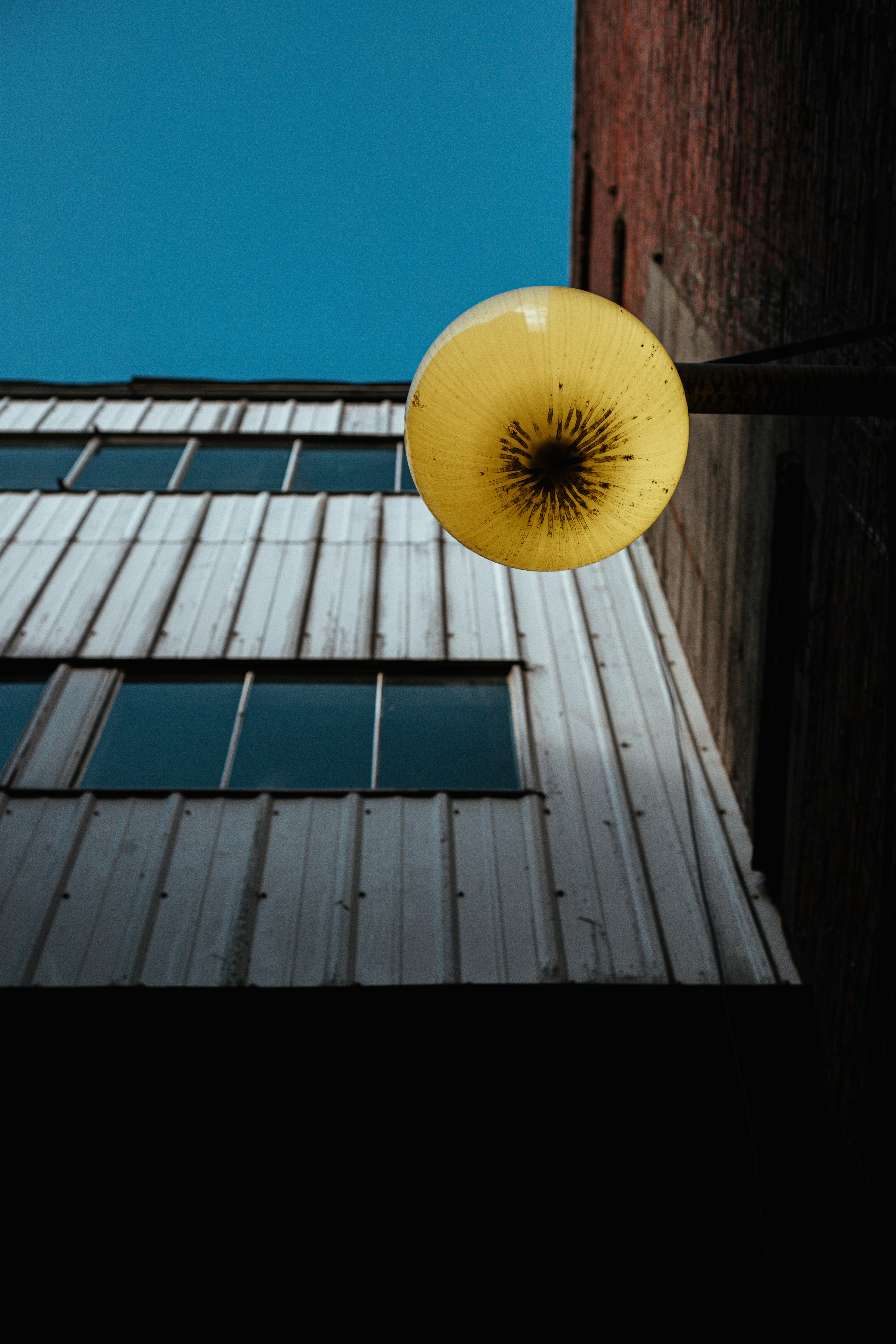 Sunlit Yellow Lantern Clinging to a Weathered Urban Facade