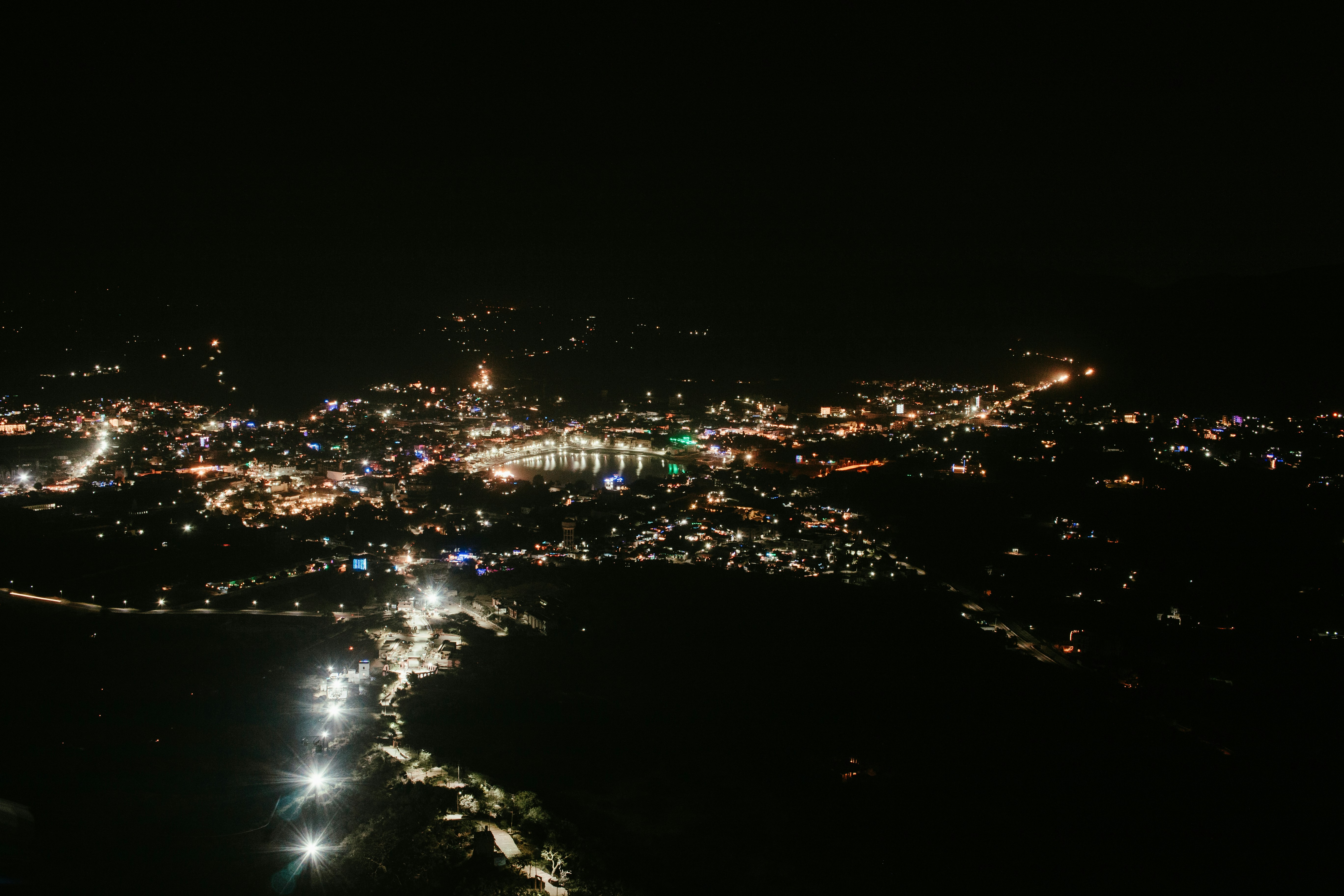 Vibrant cityscape illuminated at night, showcasing a blend of urban lights and natural landscapes. The scene captures the essence of nightlife and community.