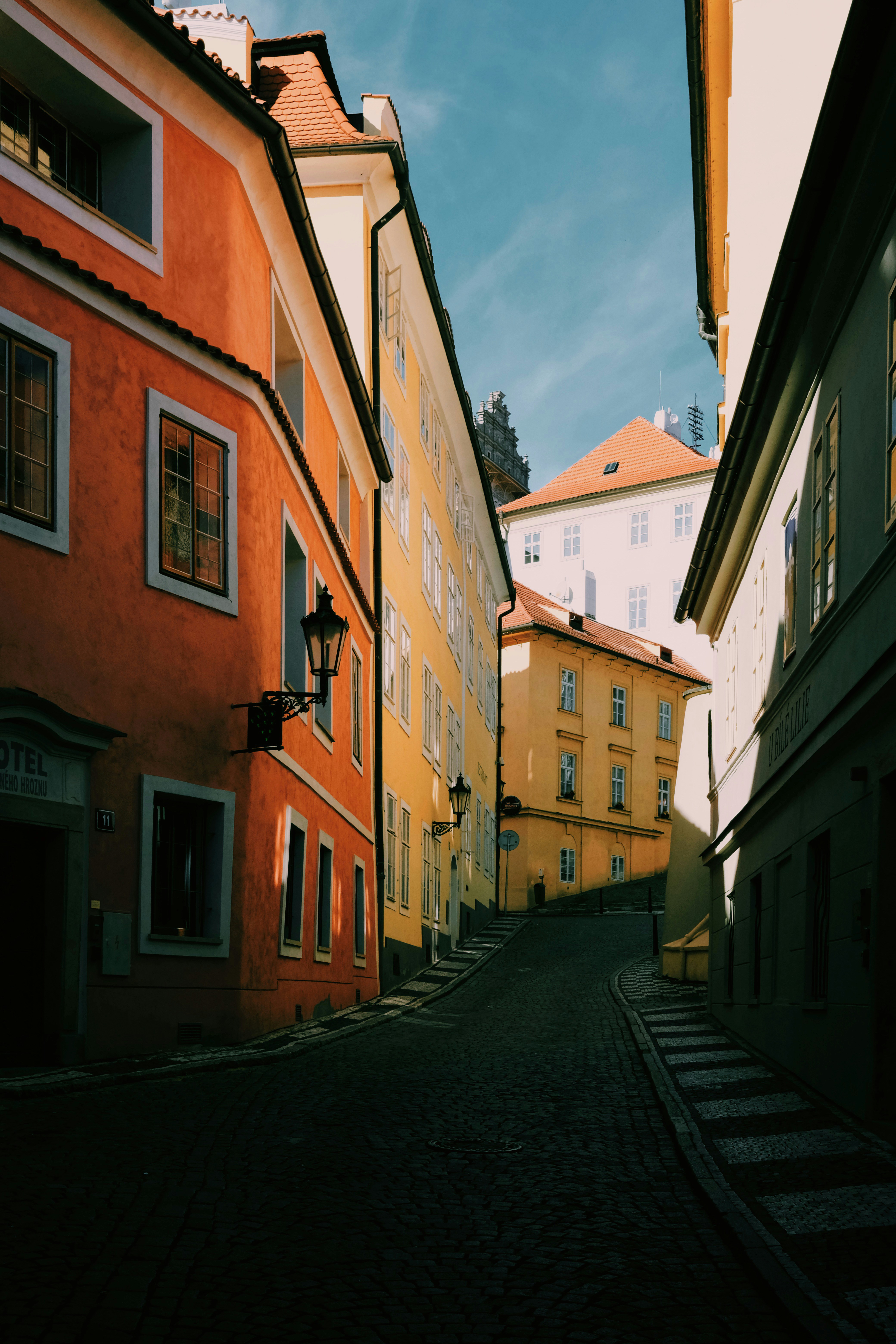 Charming cobblestone street lined with colorful buildings under a clear sky. The gentle curve of the road invites exploration.