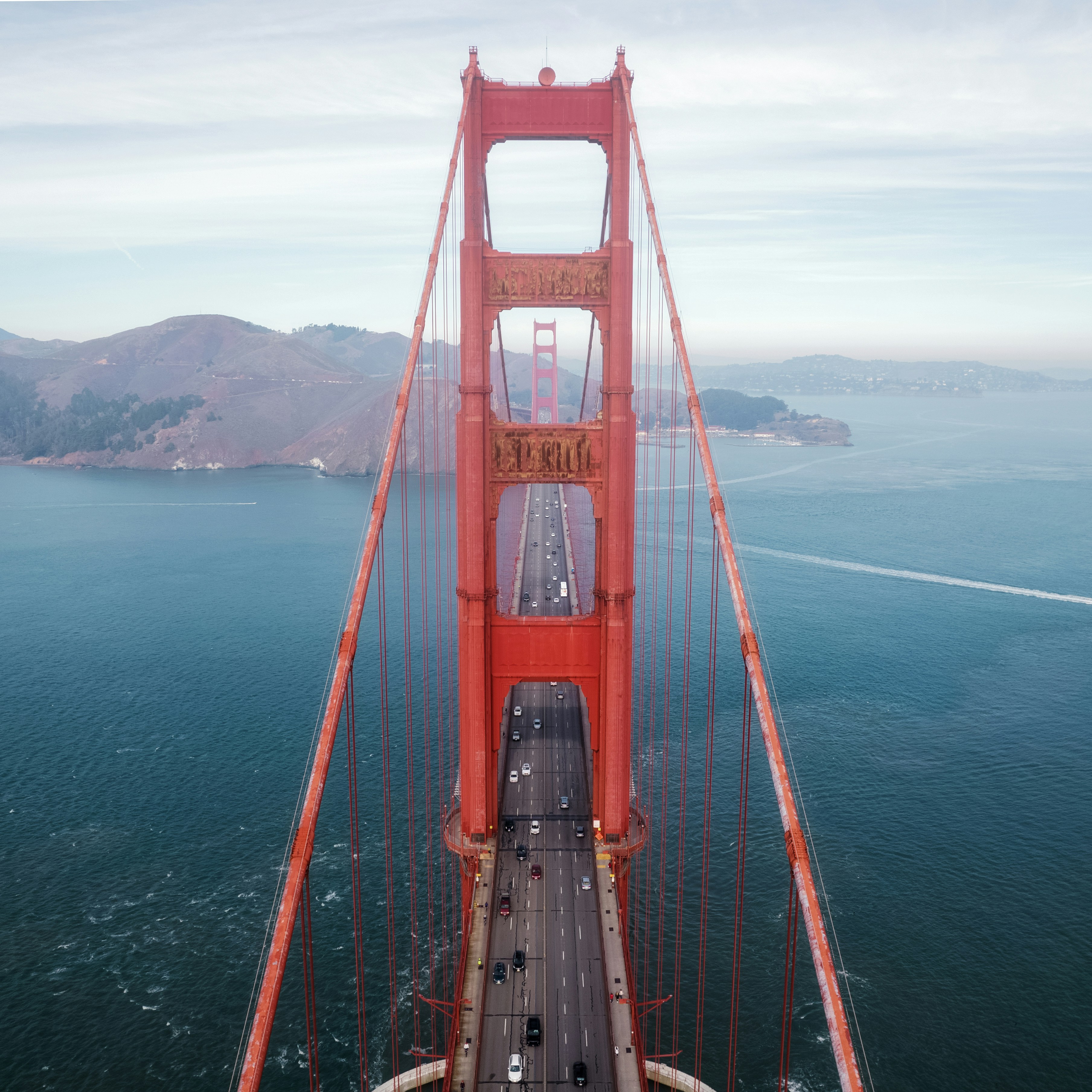 A large red bridge over water with Golden Gate Bridge in the background ...