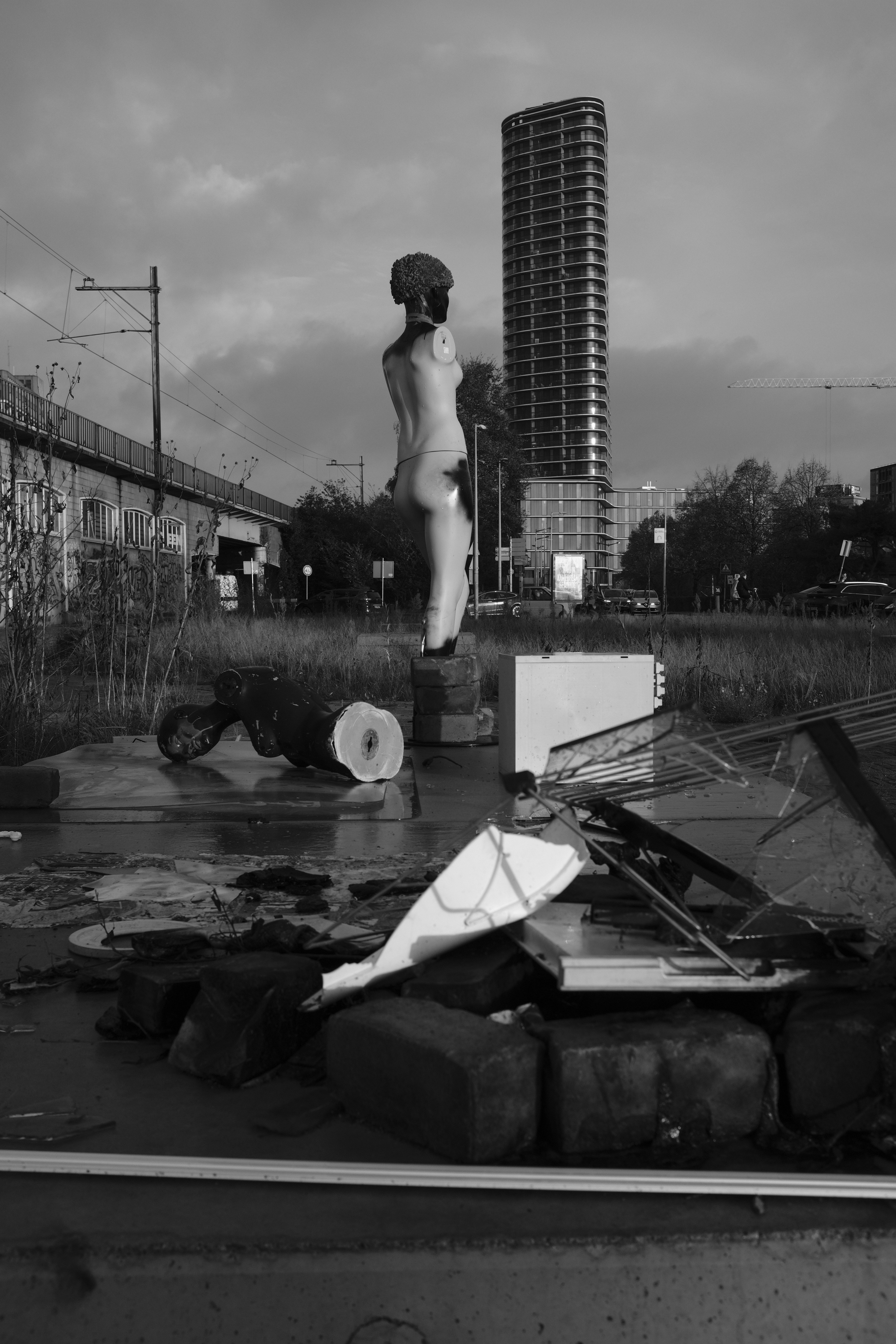 Urban Salvage: A statue amid clutter under a looming skyscraper