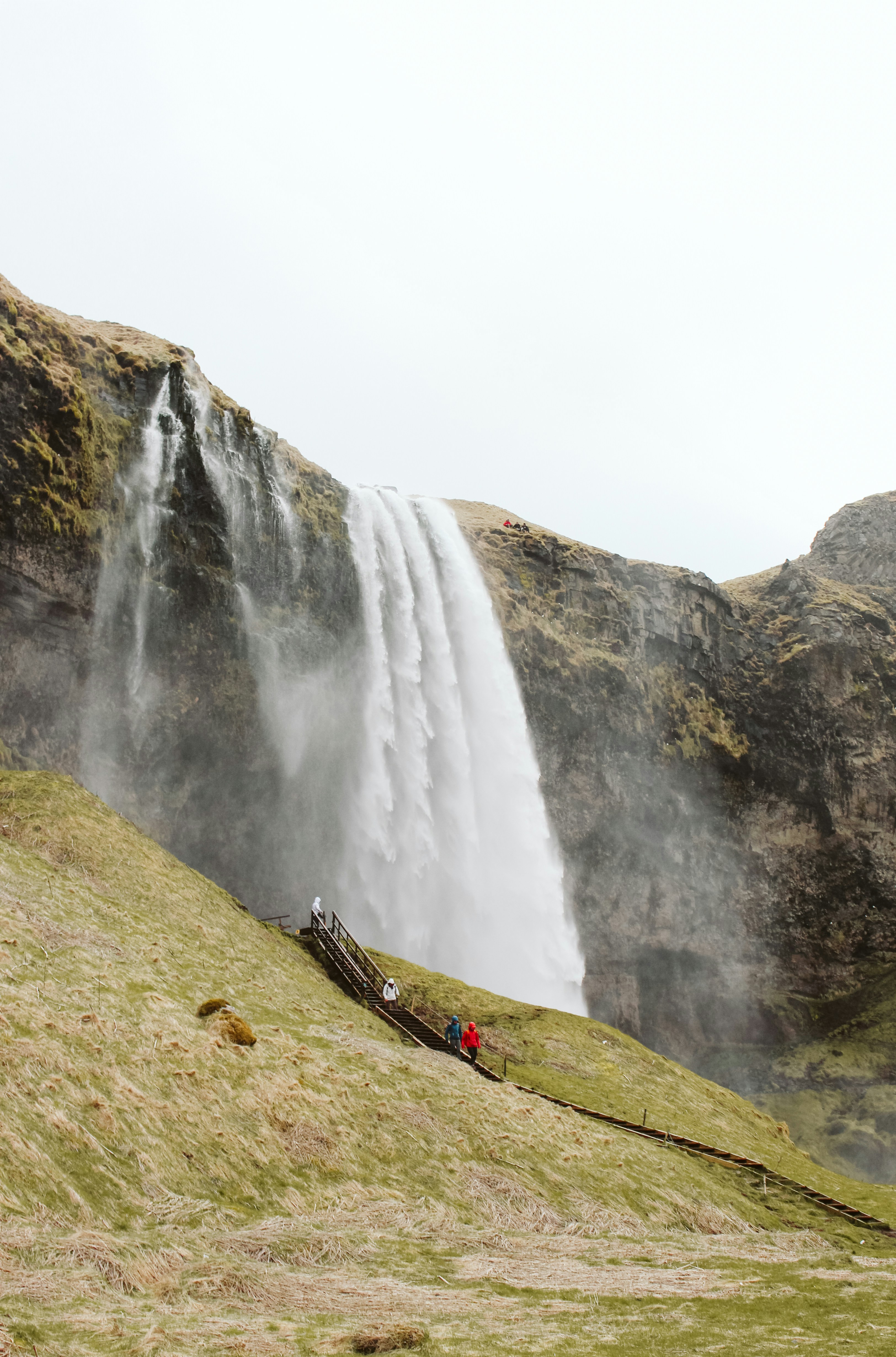 a group of people walking up a mountain with a waterfall