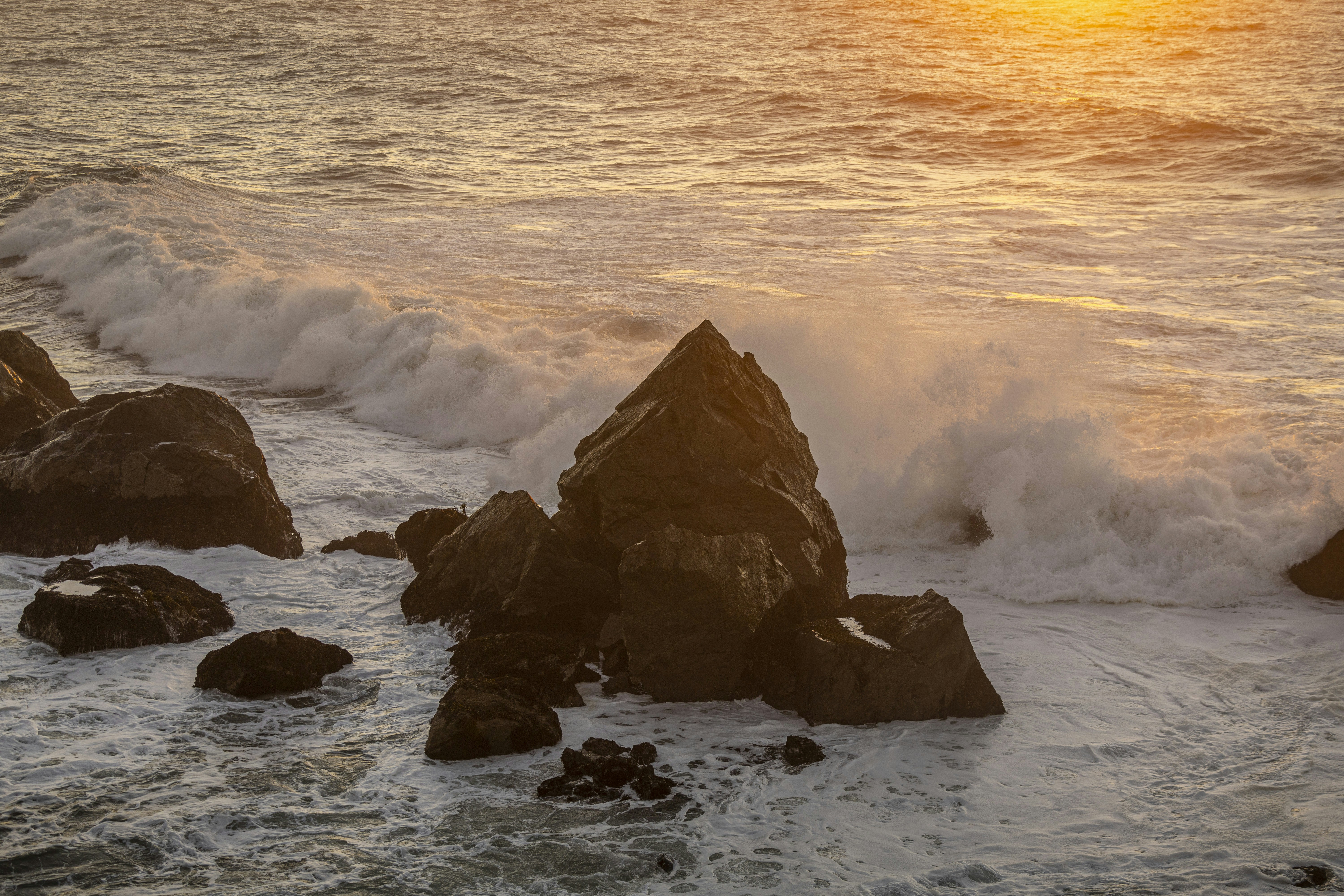 Un groupe de roches dans l’eau photo – Photo Le coucher du soleil ...
