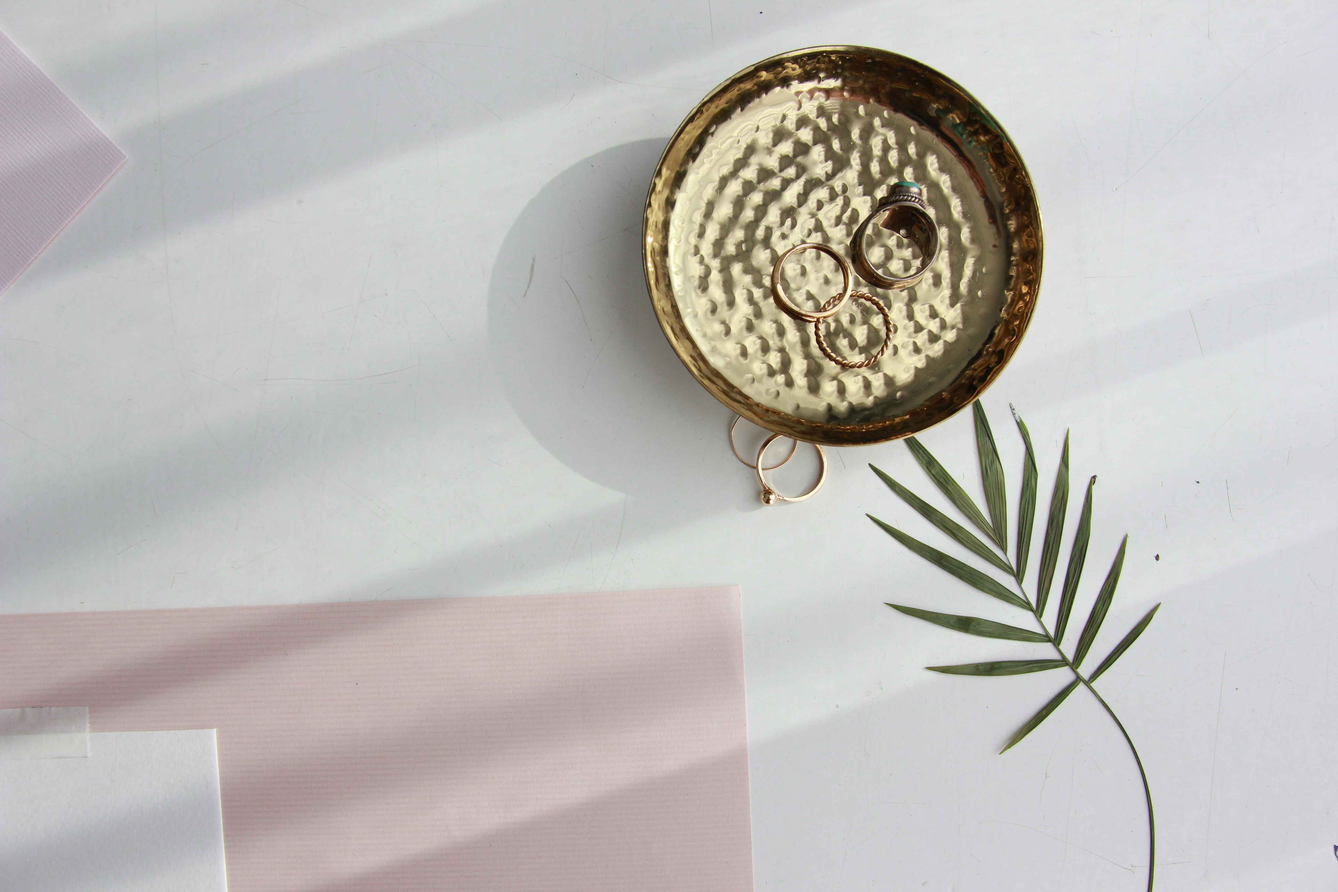 Rings in a Brass Dish: A Quiet Flat-Lay with Palm Leaf and Soft Shadows