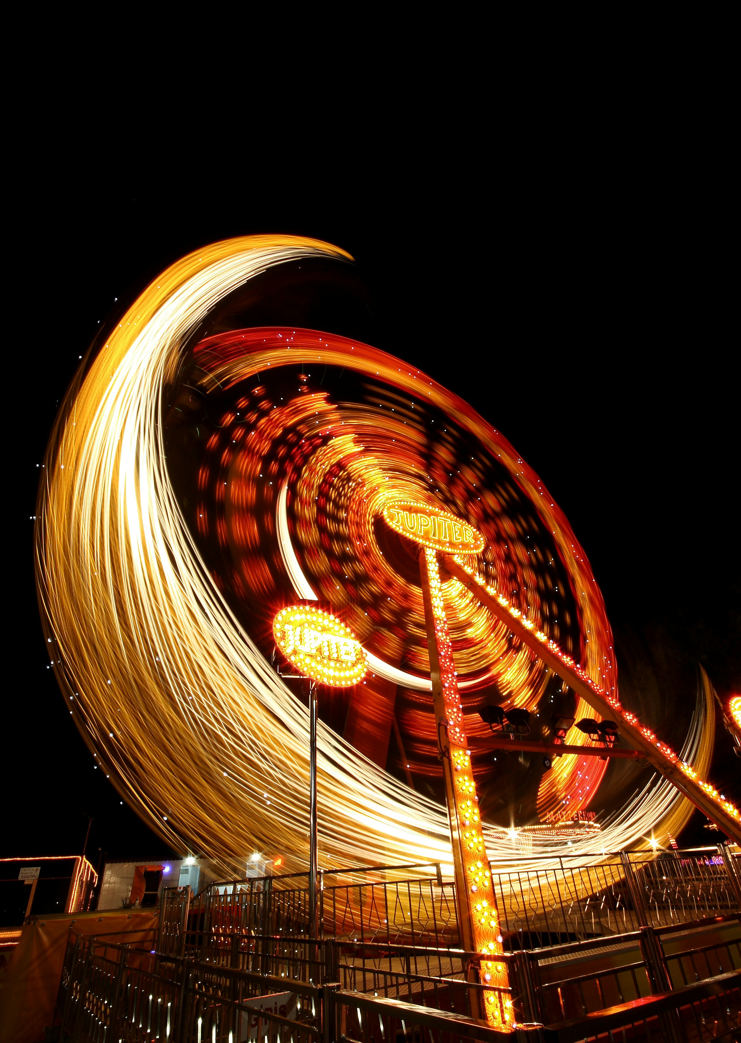 Dynamic spinning ride illuminated by vibrant lights, creating a mesmerizing circular motion against the night sky.