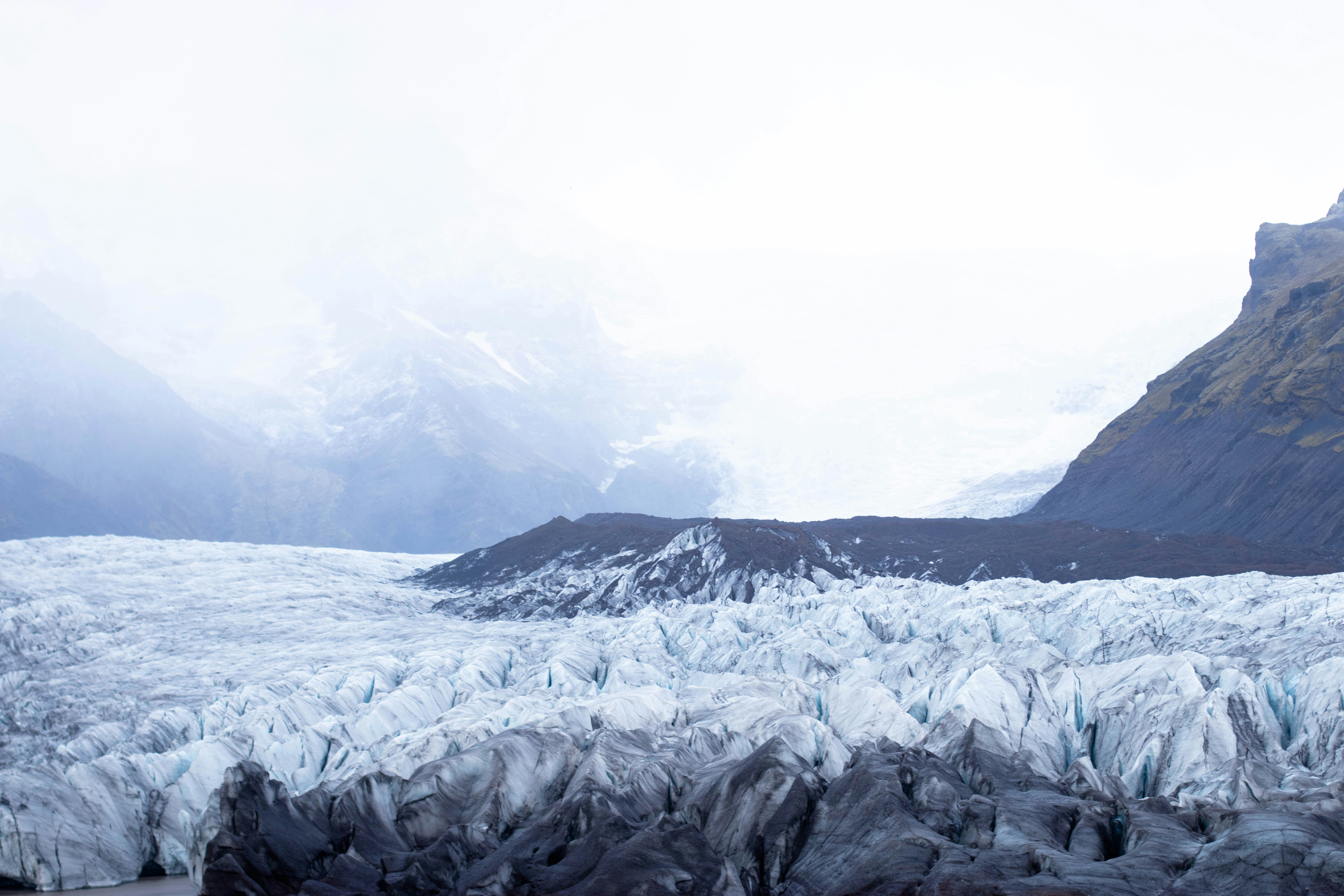 Blue Icefield at Dusk: Cracks and Moraine Beneath Misty Peaks
