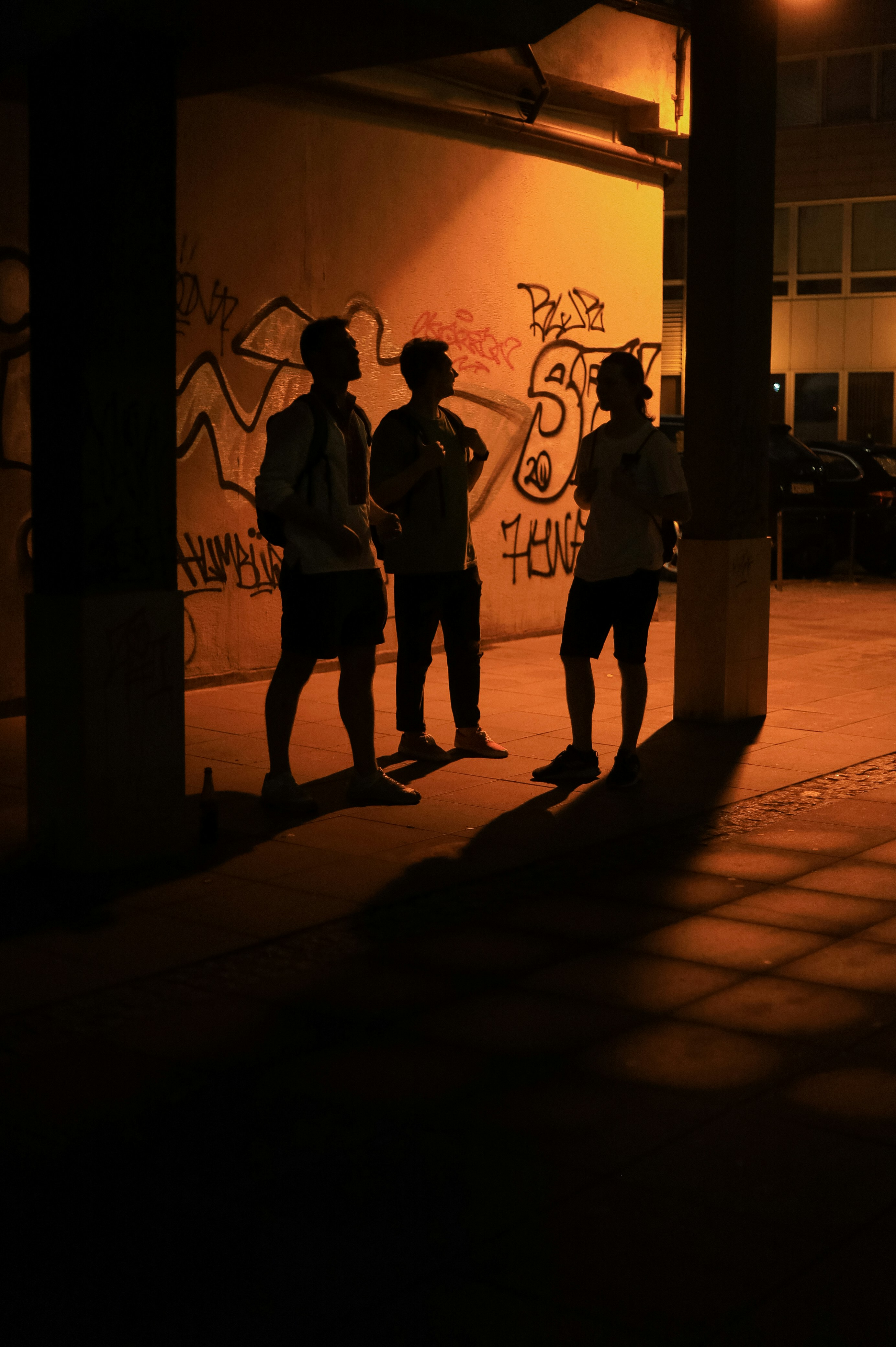 Shadowed Trio in Neon Graffiti Underpass