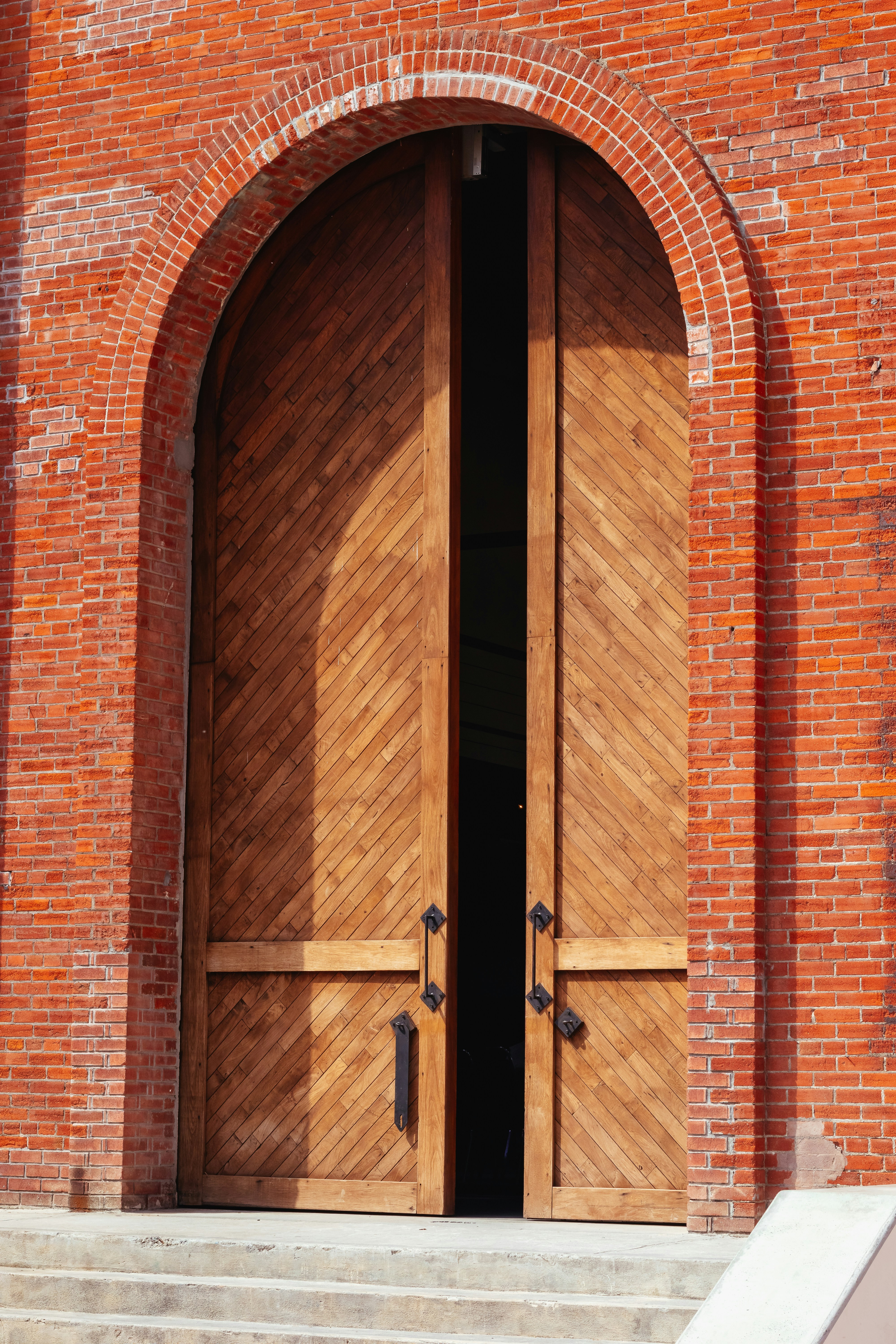 Arched Brick Portal: Sunlit Diagonal-Panel Doors