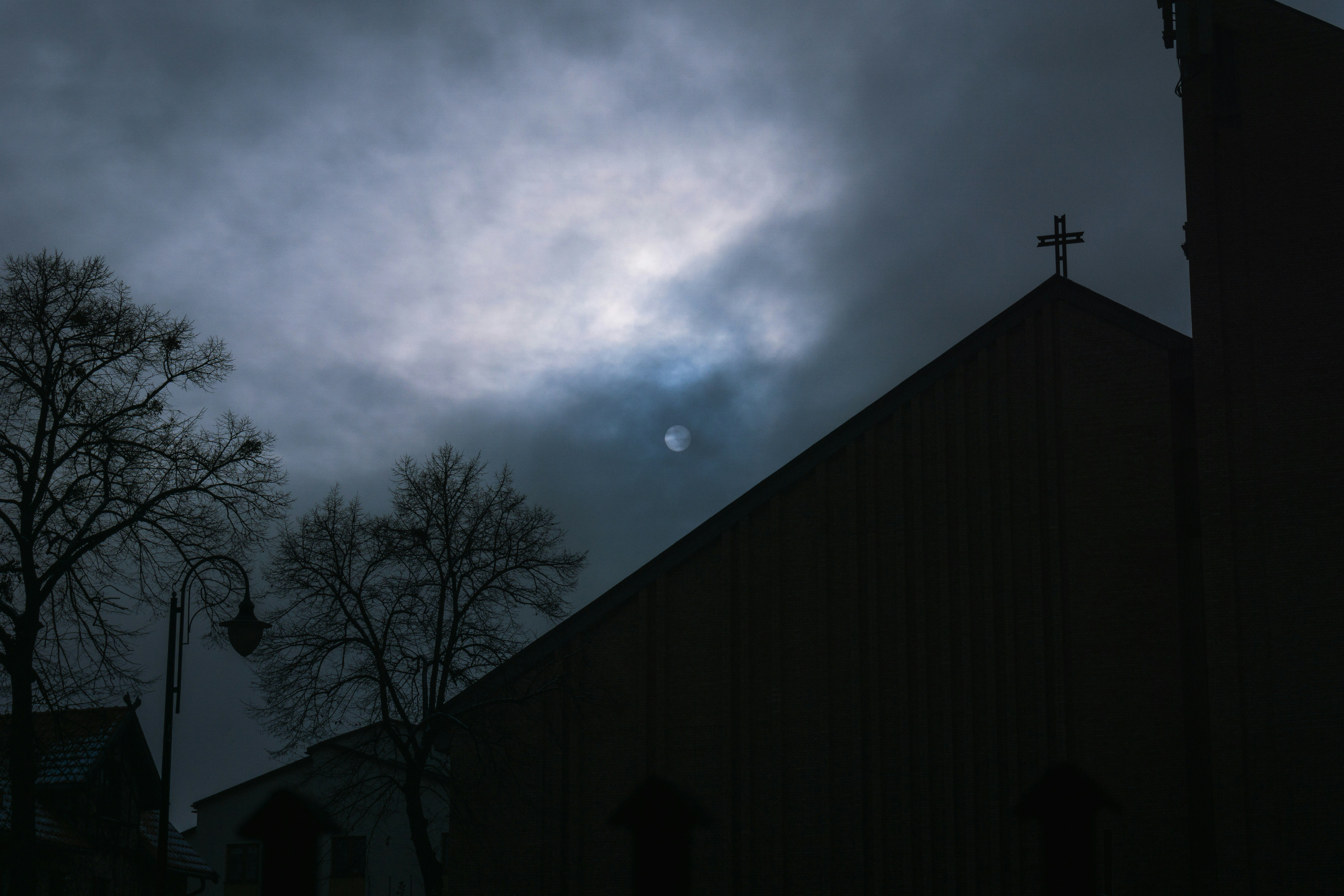Cross on the Ridge: Moonlit Church Silhouette Under Brooding Clouds