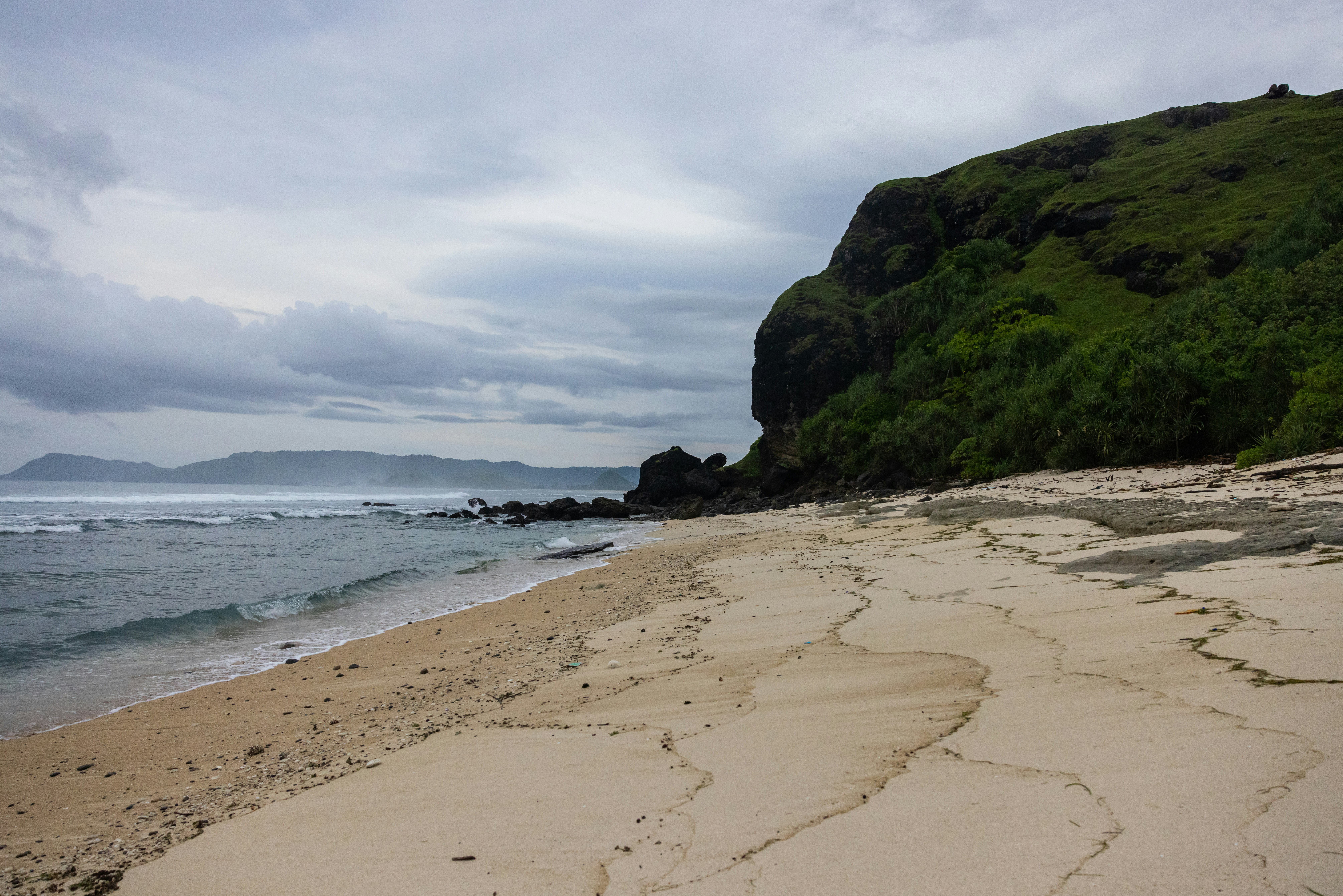 Foto Una playa con una colina y agua – Imagen Playa Tanjung Aan gratis ...